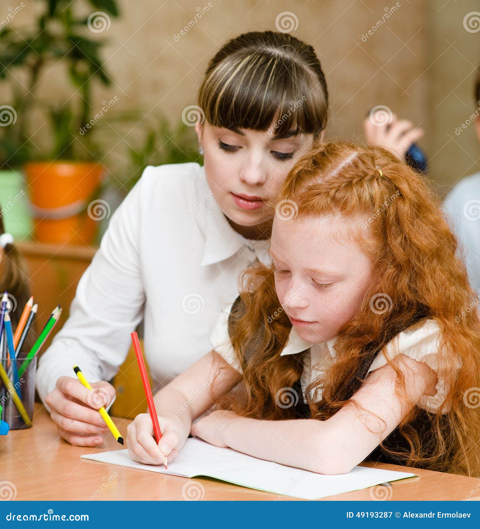 The Teacher Helps Schoolgirls In The Lesson, Prompting How To Solve The ... The Teacher Helps Schoolgirls In The Lesson, Prompting How To Solve The ...
