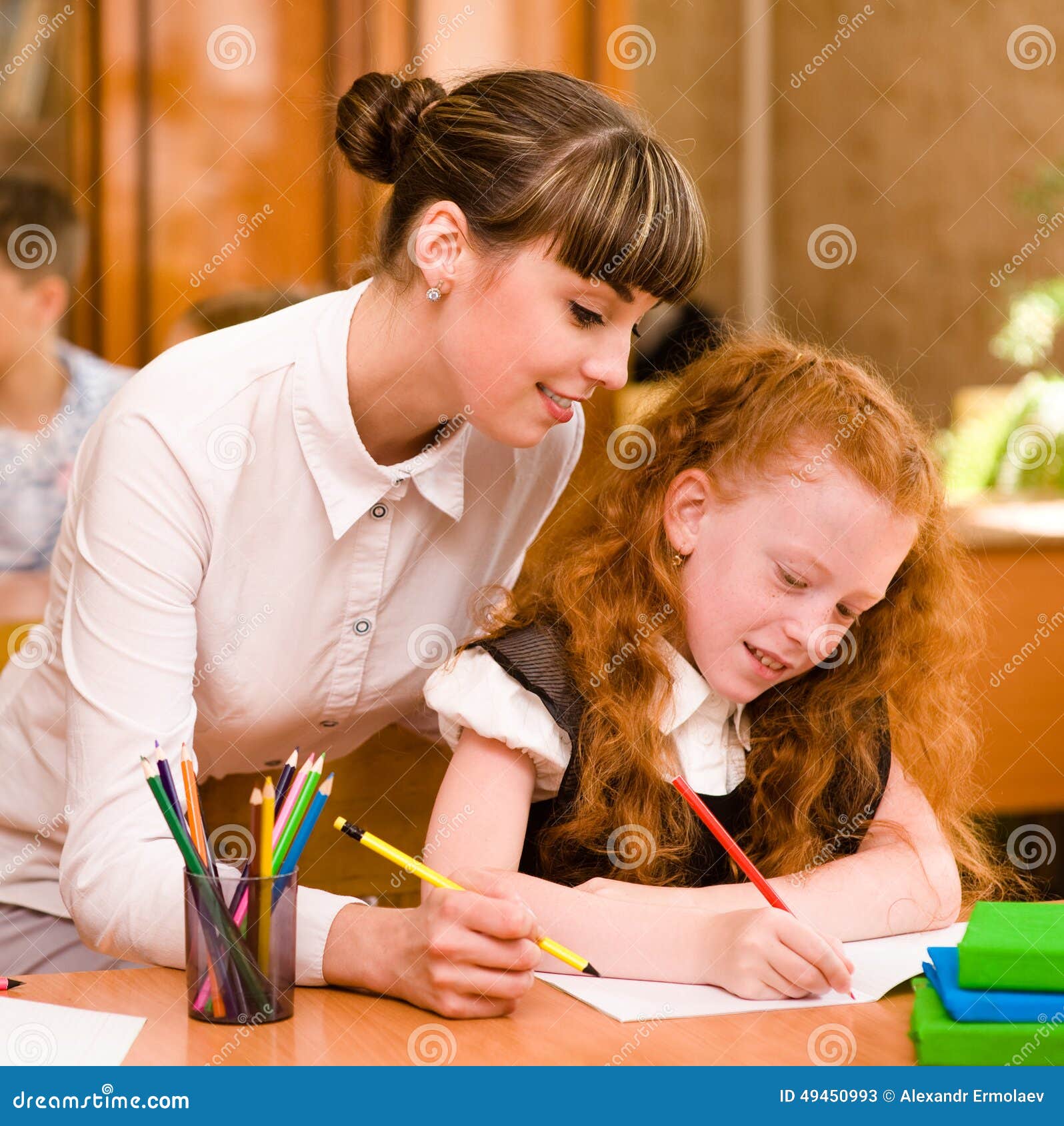 Teacher Helps the Student with Schoolwork in School Classroom Stock ...