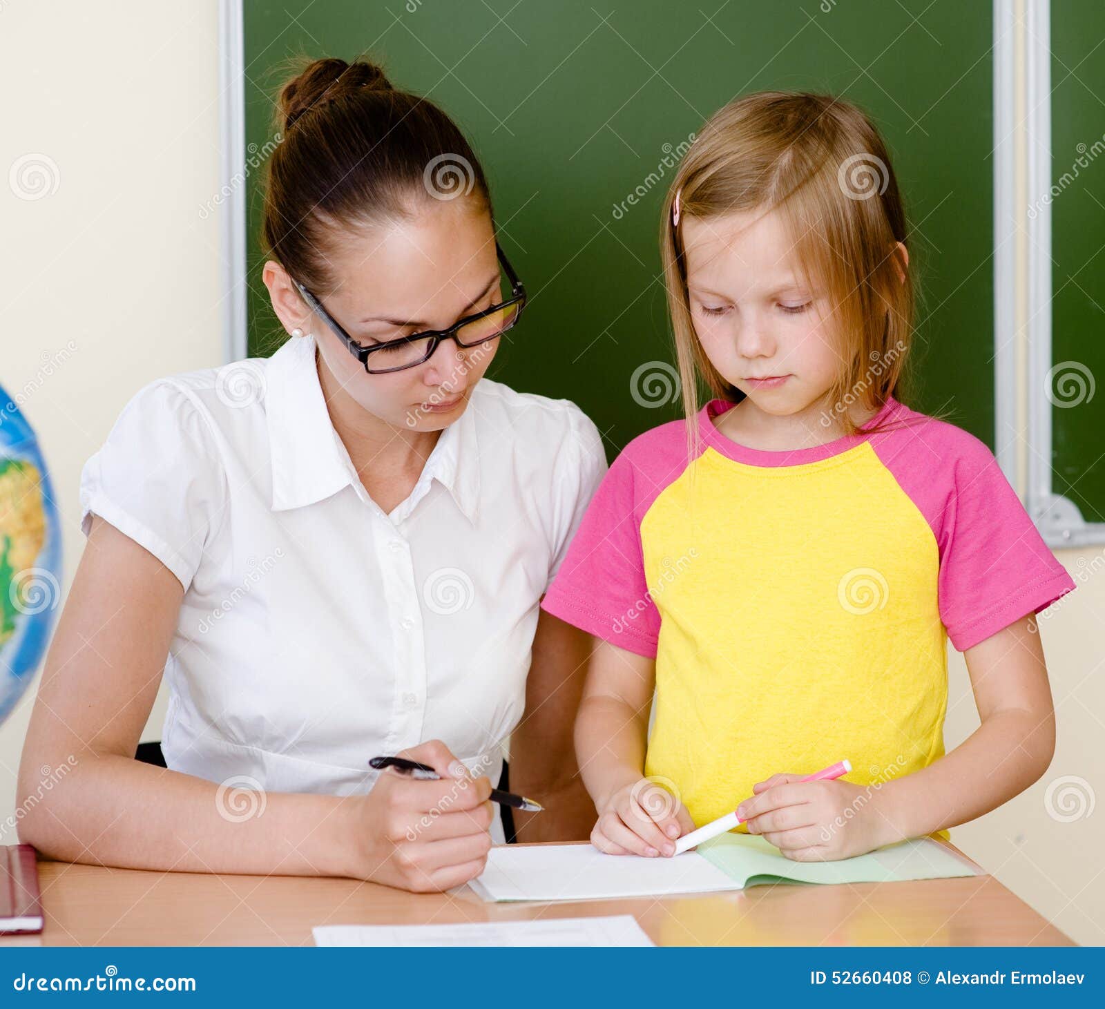 The Teacher Helps Schoolgirls In The Lesson, Prompting How To Solve The ... The Teacher Helps Schoolgirls In The Lesson, Prompting How To Solve The ...