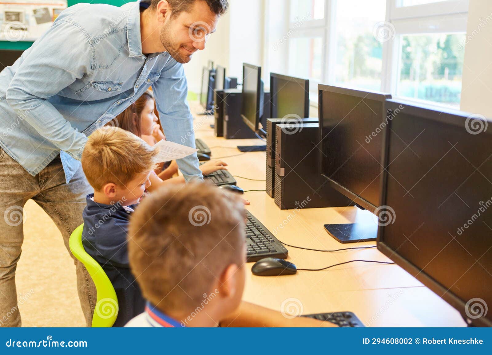 Teacher Leaning on Desk with Students in Computer Class Stock Photo ...