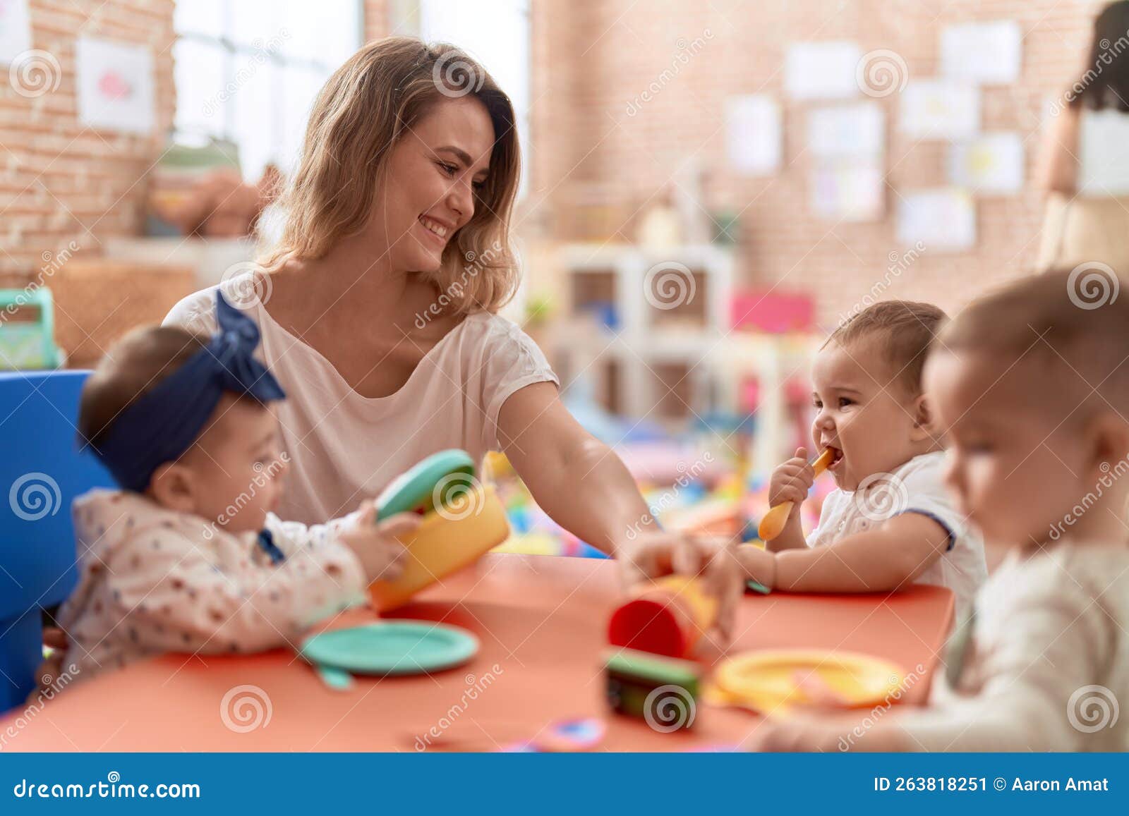 Teacher and Preschool Students Learning To Eat Sitting on Table at ...