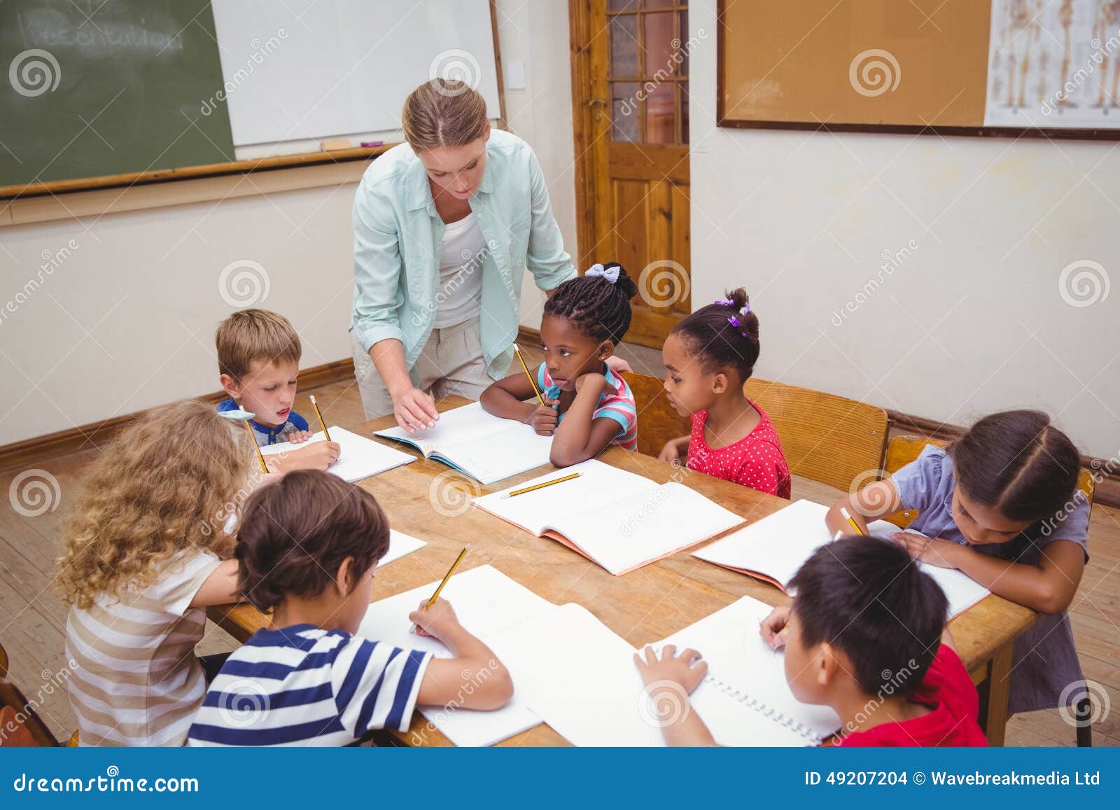 Teacher and Pupils Working at Desk Together Stock Photo - Image of ...