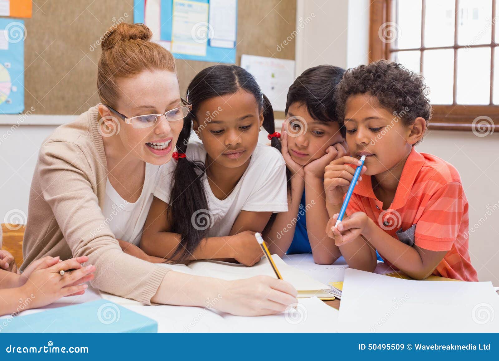 Teacher and Pupils Working at Desk Together Stock Image - Image of ...