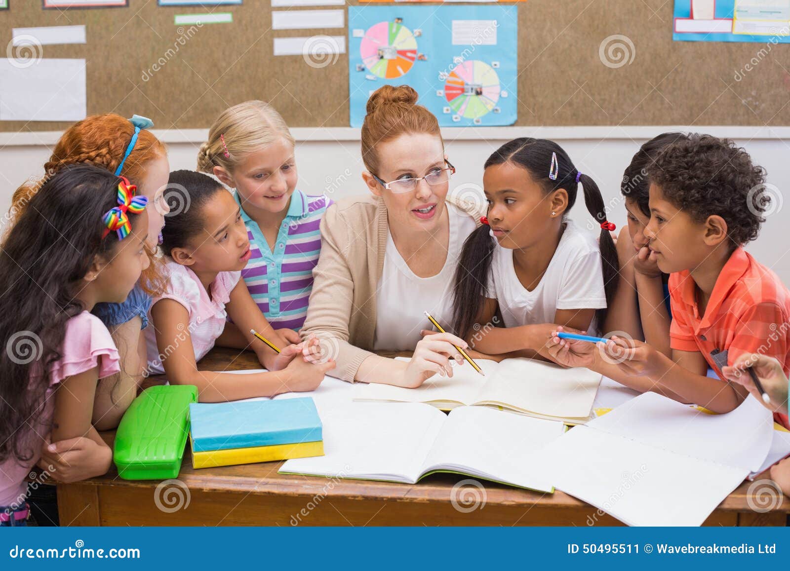 Teacher and Pupils Working at Desk Together Stock Image - Image of ...