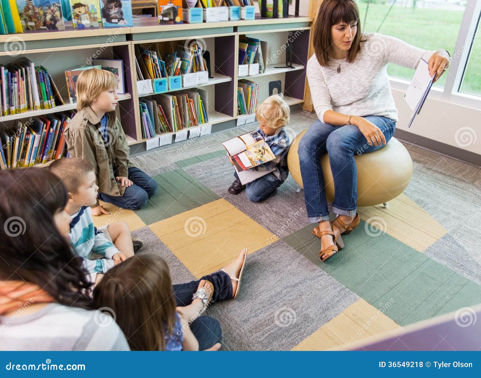Teacher Reading Book To Children in Library Stock Photo - Image of ...