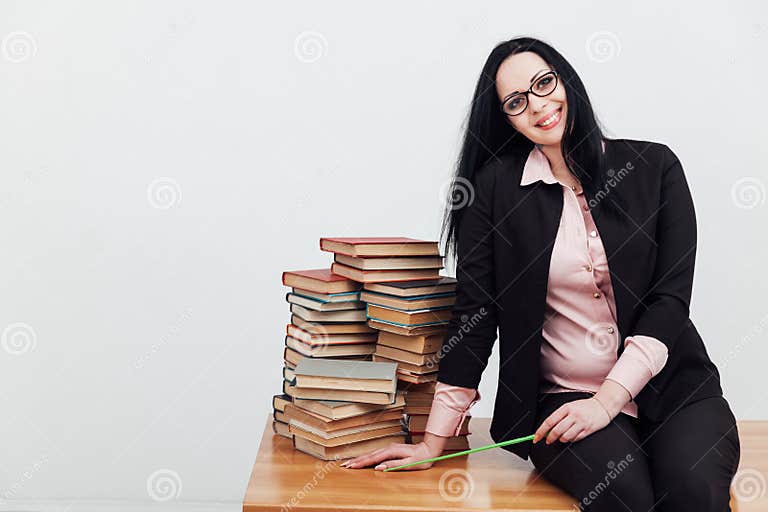 A Teacher with a School Pointer Sits on a Table with Many Books Stock ...