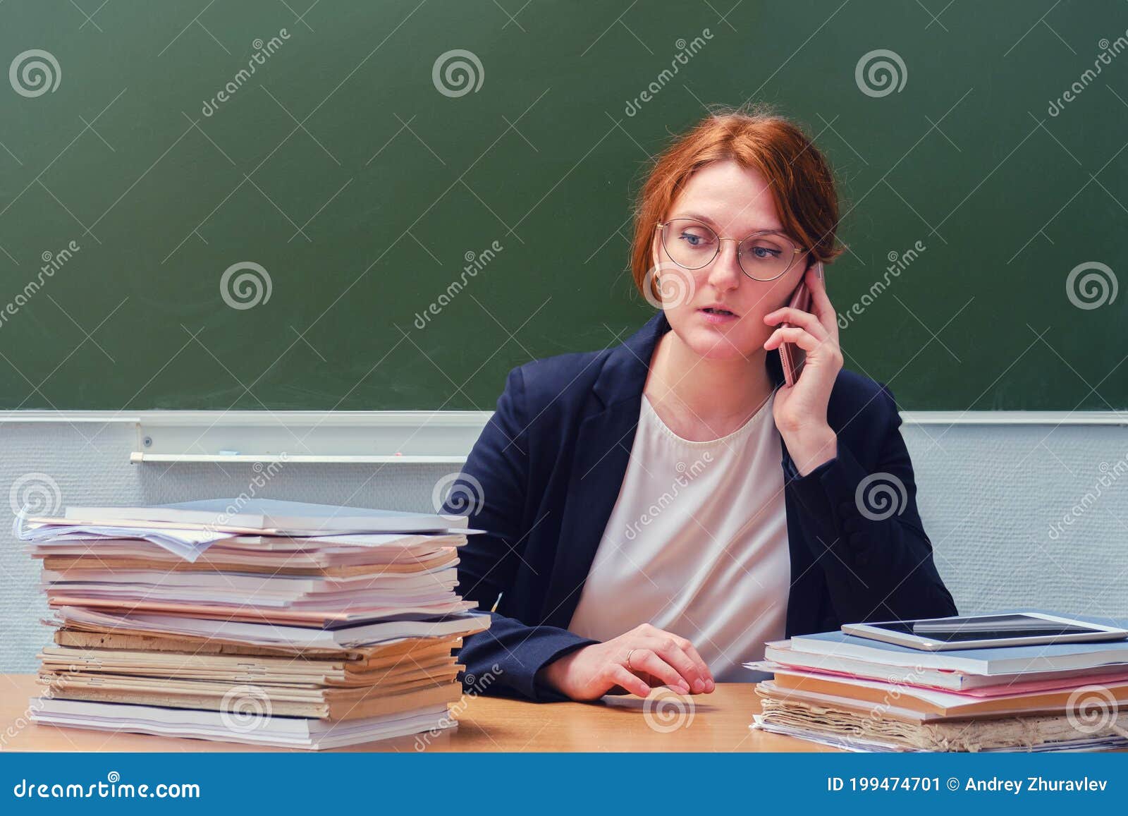 Teacher Sits at a Desk and Speaks by Phone at the School Blackboard ...