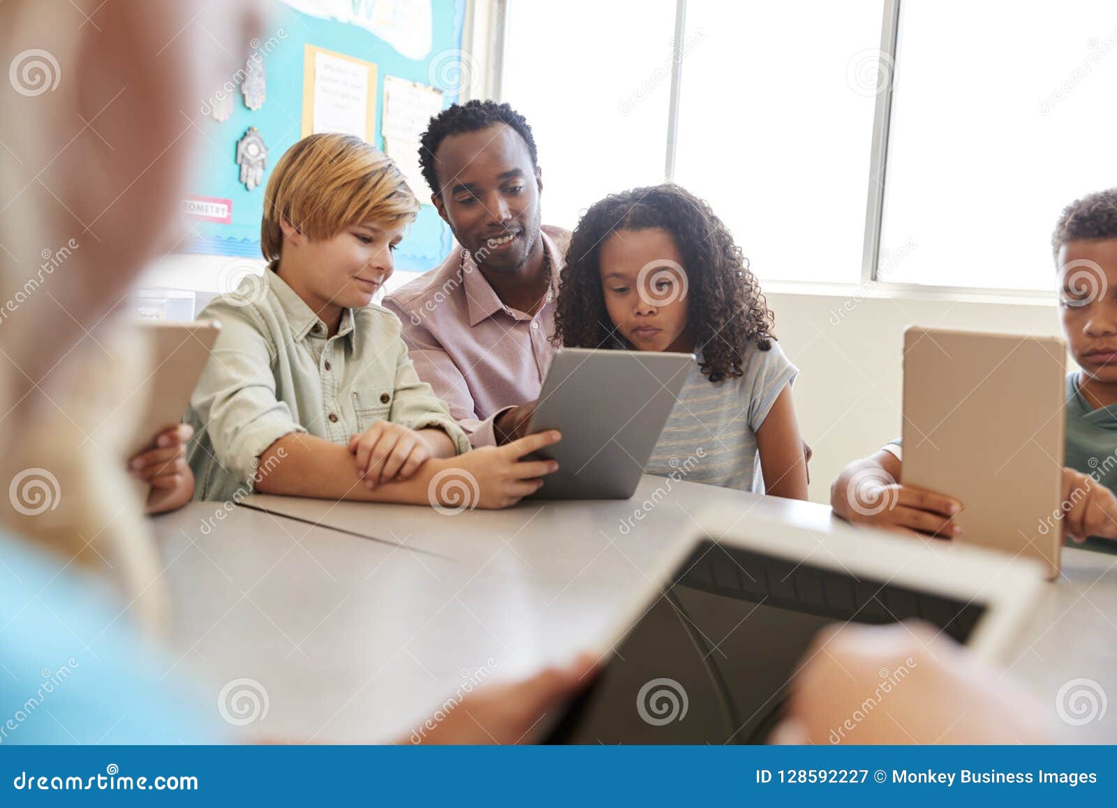 Teacher Sits with Young Kids Using Computers in School Class Stock ...