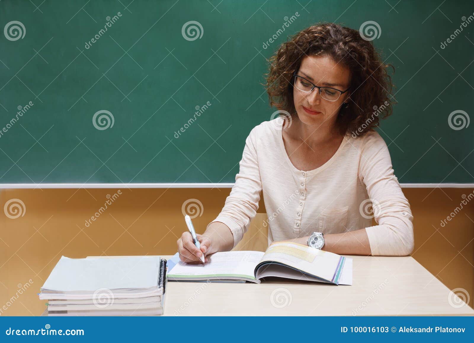 The Teacher is Sitting at the Desk and Checking School Notebooks Stock ...