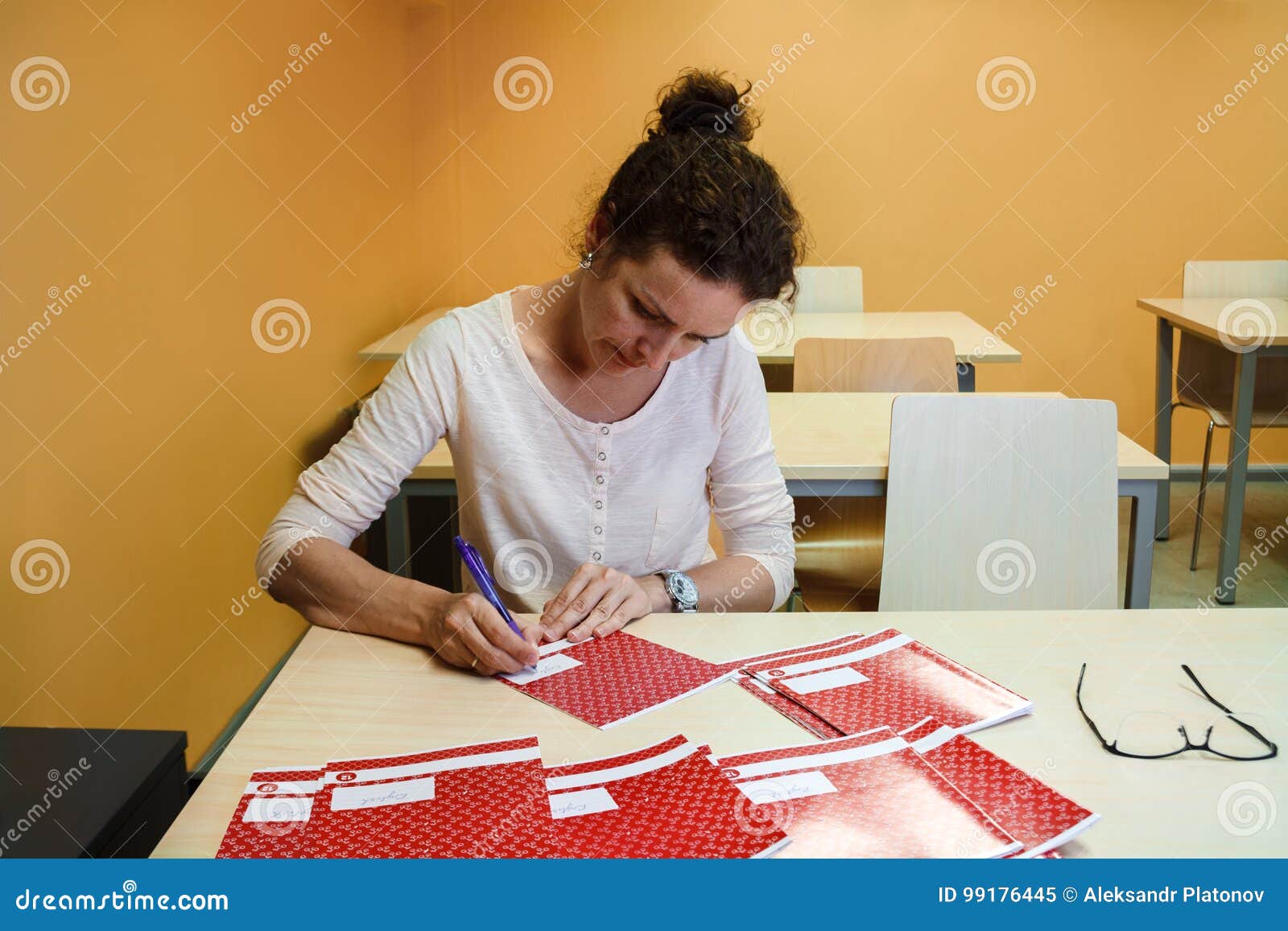 The Teacher is Sitting at the Desk and Checking School Notebooks Stock ...