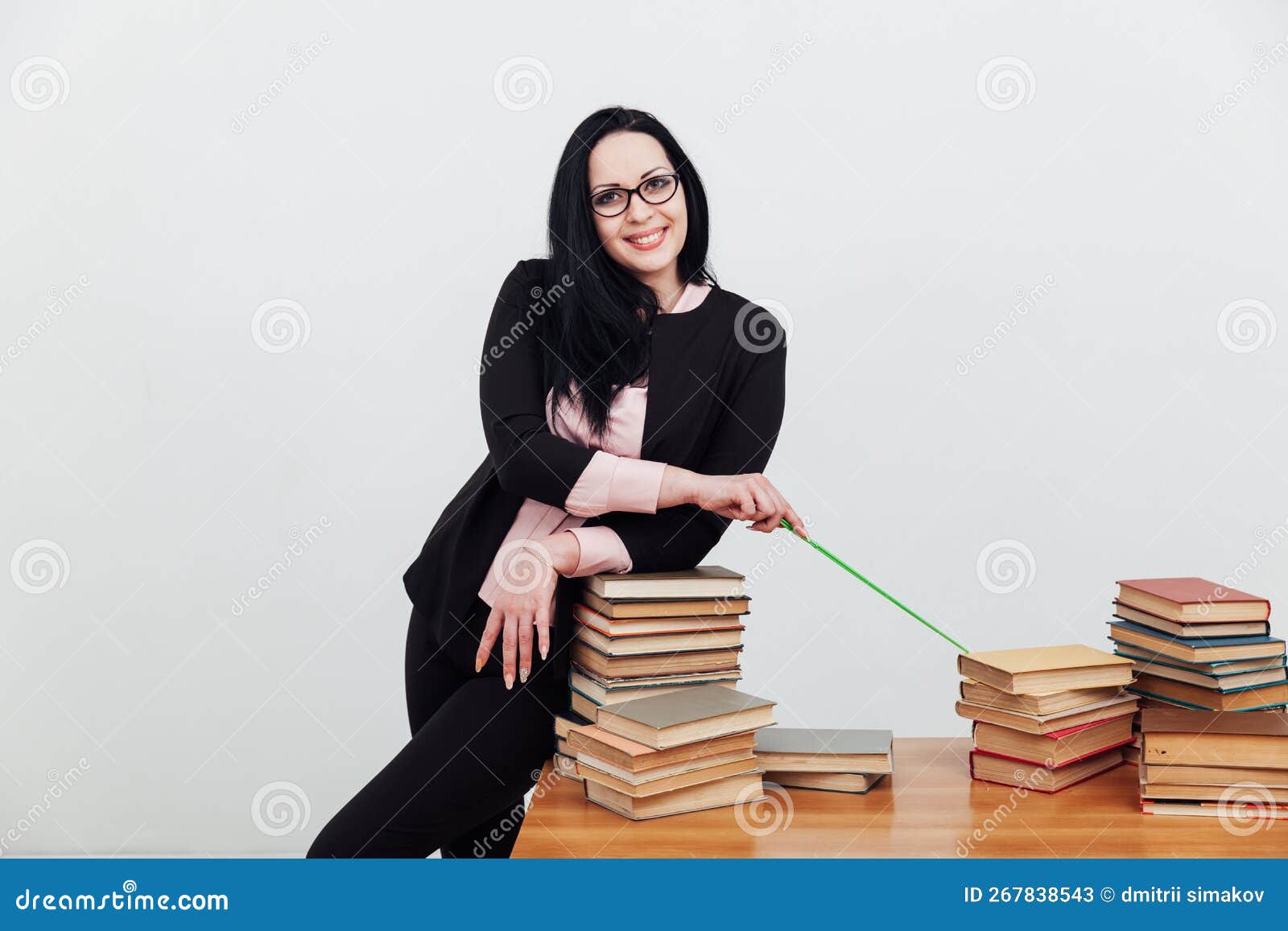 A Teacher with a School Pointer Points To a Stack of Books To Read ...