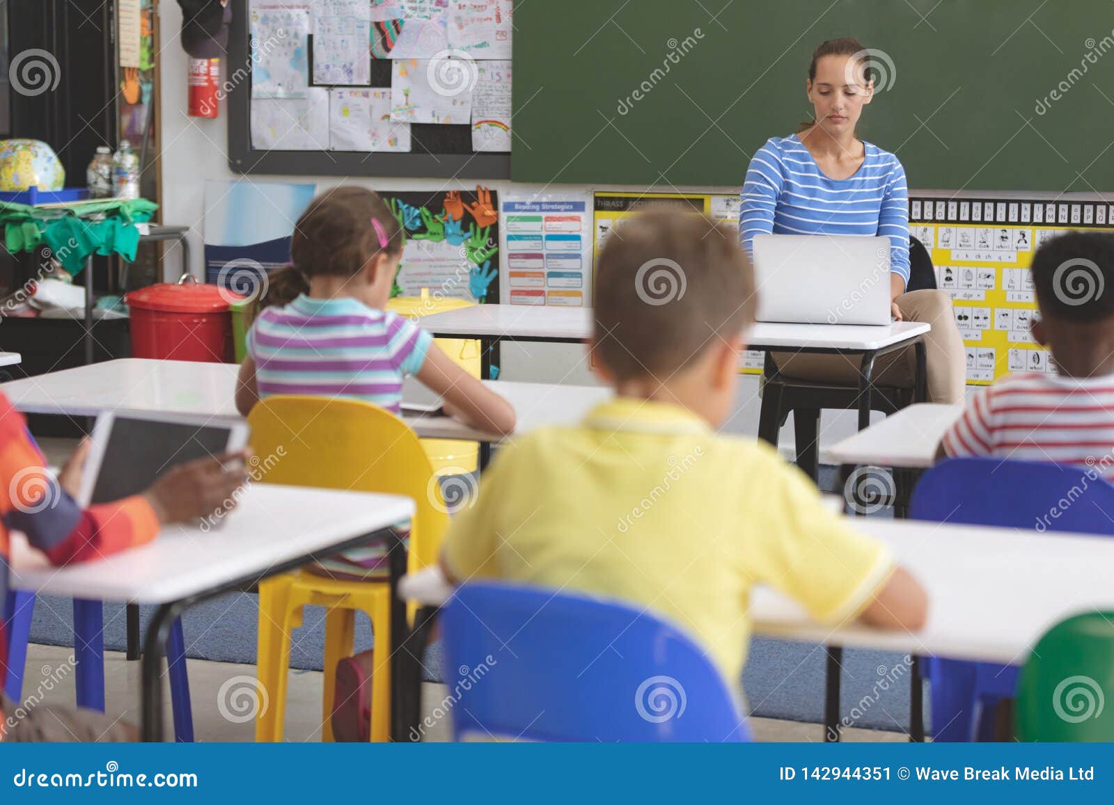 Teacher Using Laptop in Classroom while School Kids Studying Stock ...
