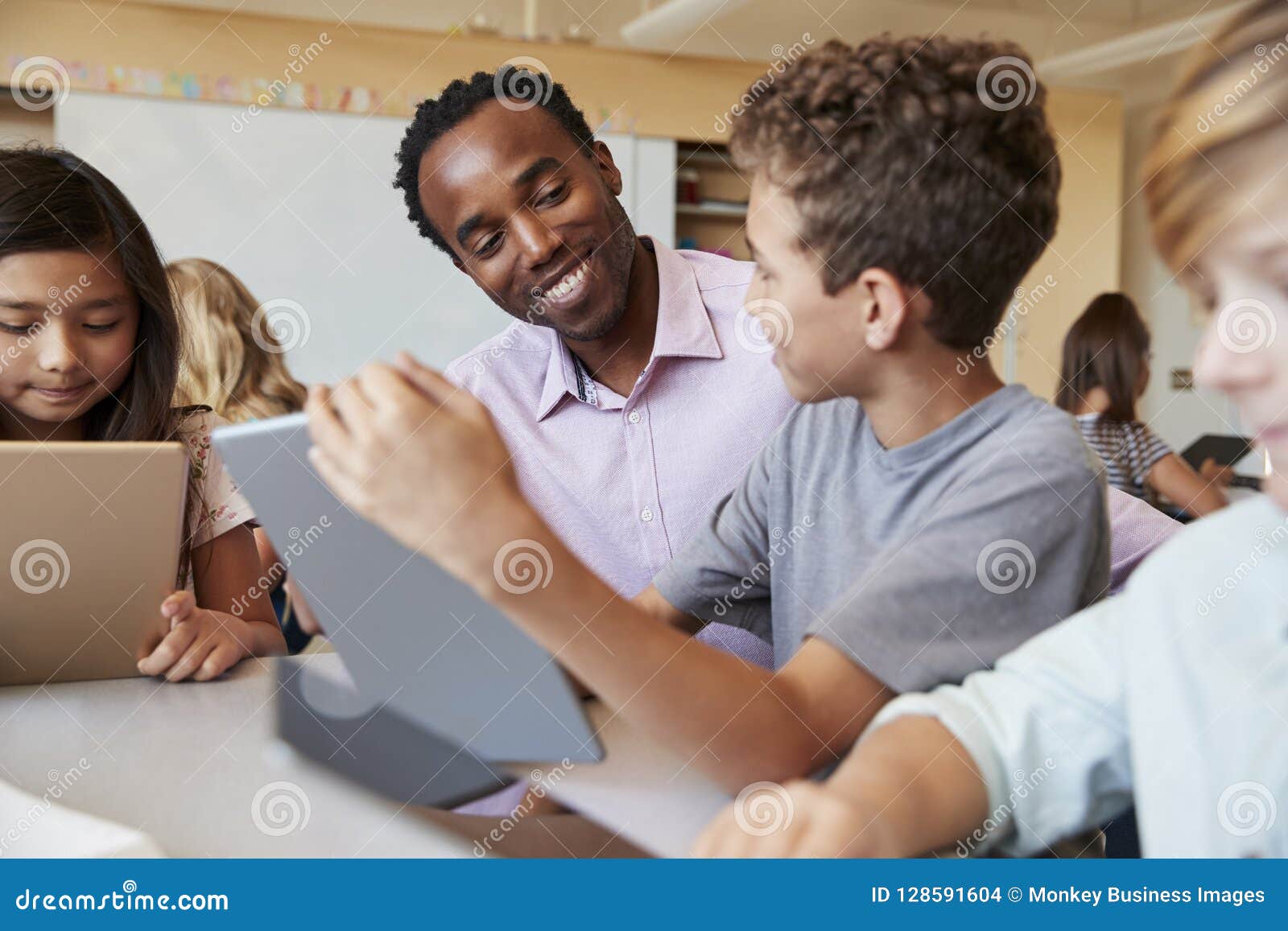 Teacher Using Tablet Computer at Desk with School Kids Stock Photo ...