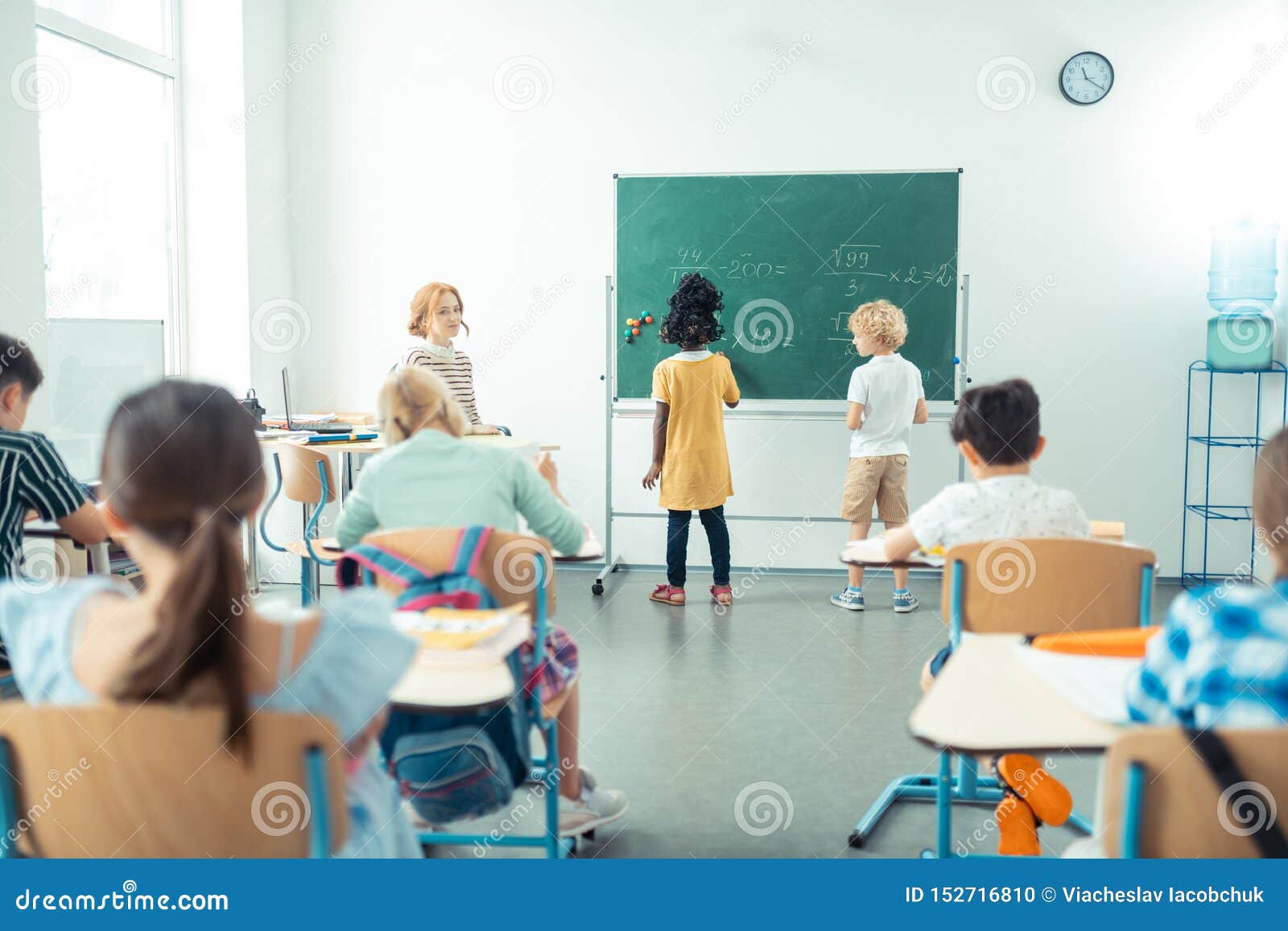 Teacher Watching Her Class while Two Kids Writing. Stock Photo - Image ...