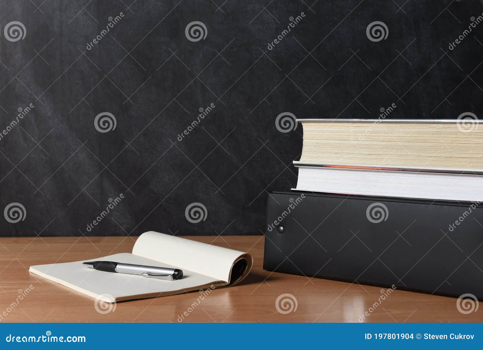 Teachers Desk with Note Pad and Pen and Books Stacked on a Binder Stock ...
