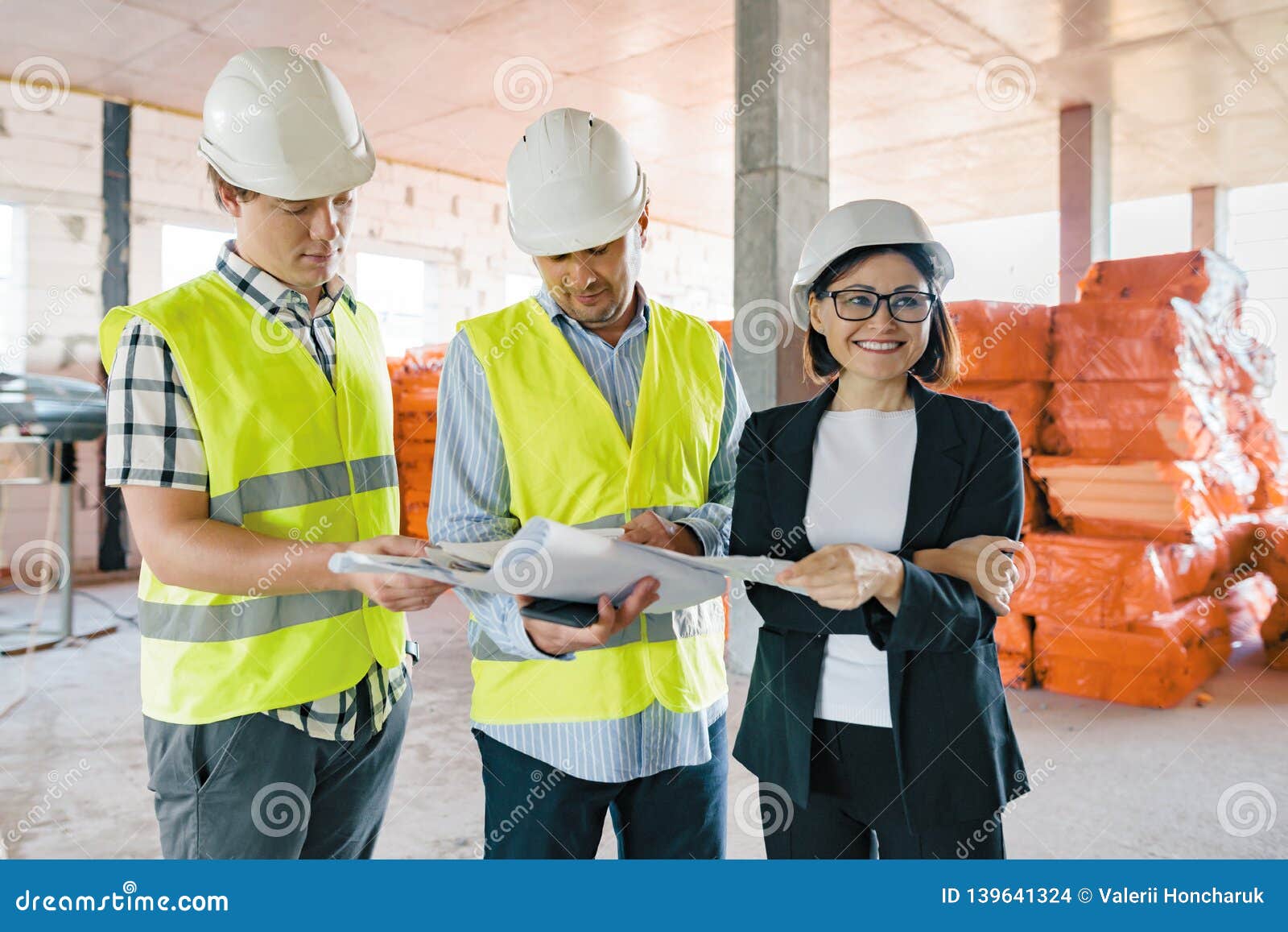 Team of Builders Engineers at Construction Site, Reading Blueprint ...