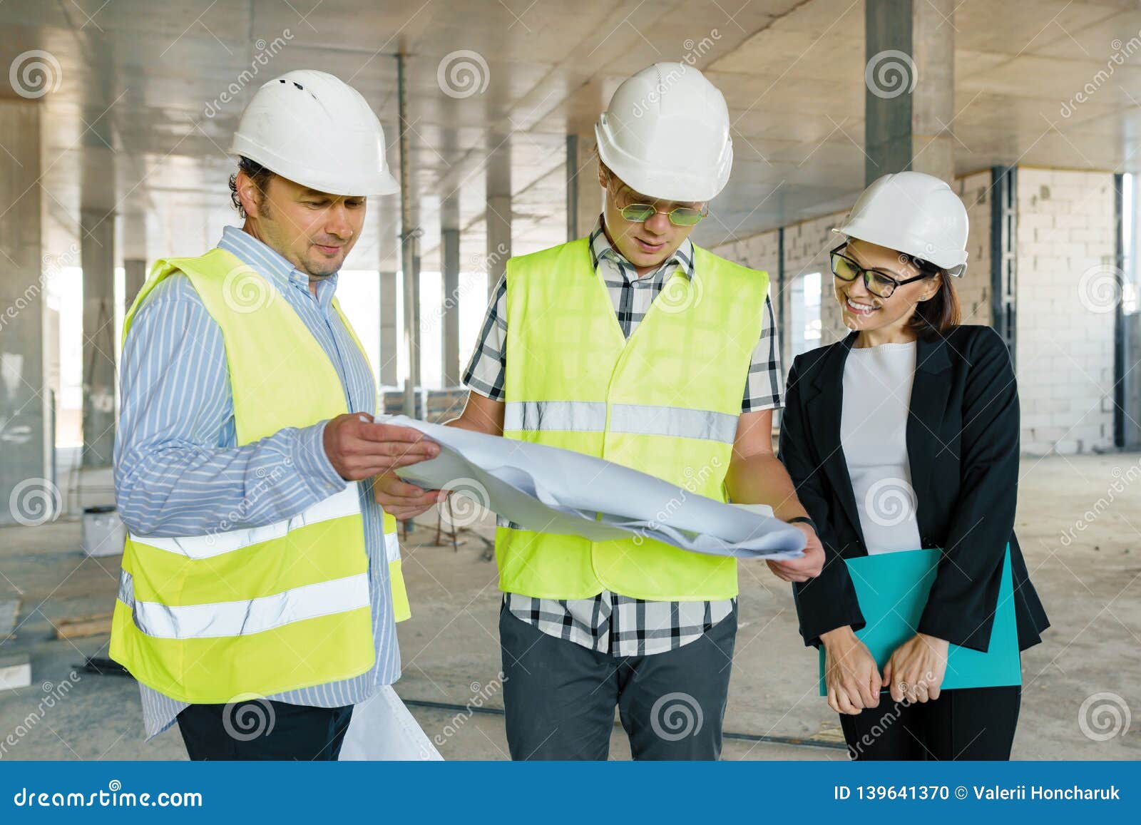 Team of Builders Engineers at Construction Site, Reading Blueprint ...