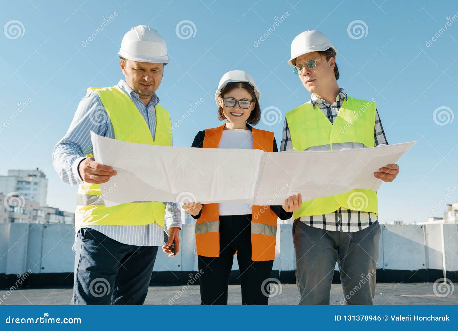 Team of Builders Engineers at a Construction Site, Reading Blueprint ...