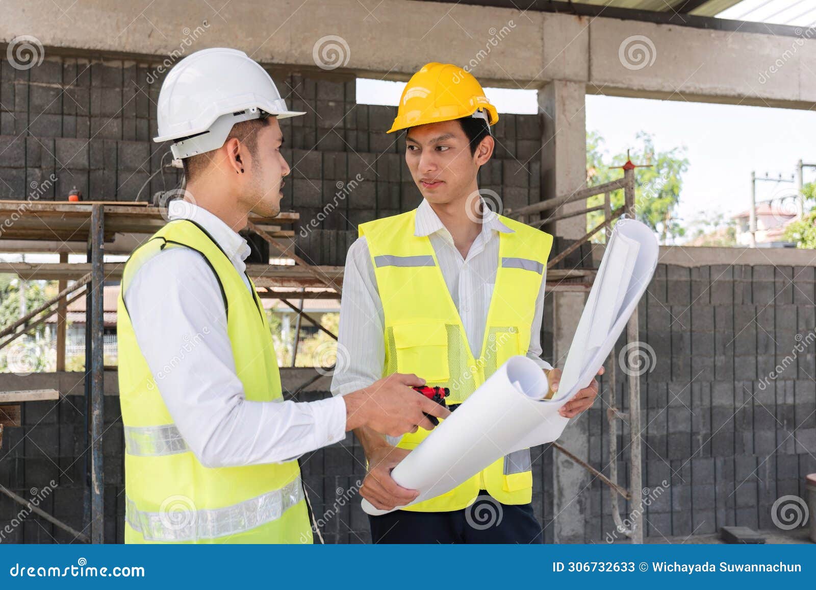 A Team of Civil Engineers and Foremen Discuss Construction Project Plans. Holding Project Plan ...