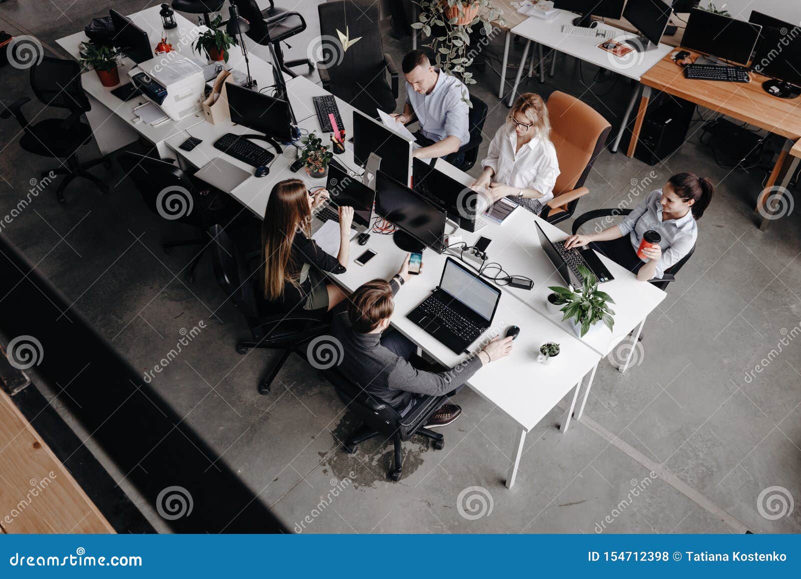 Team of Colleagues Works with Laptop and Documents Sitting at the Desks ...