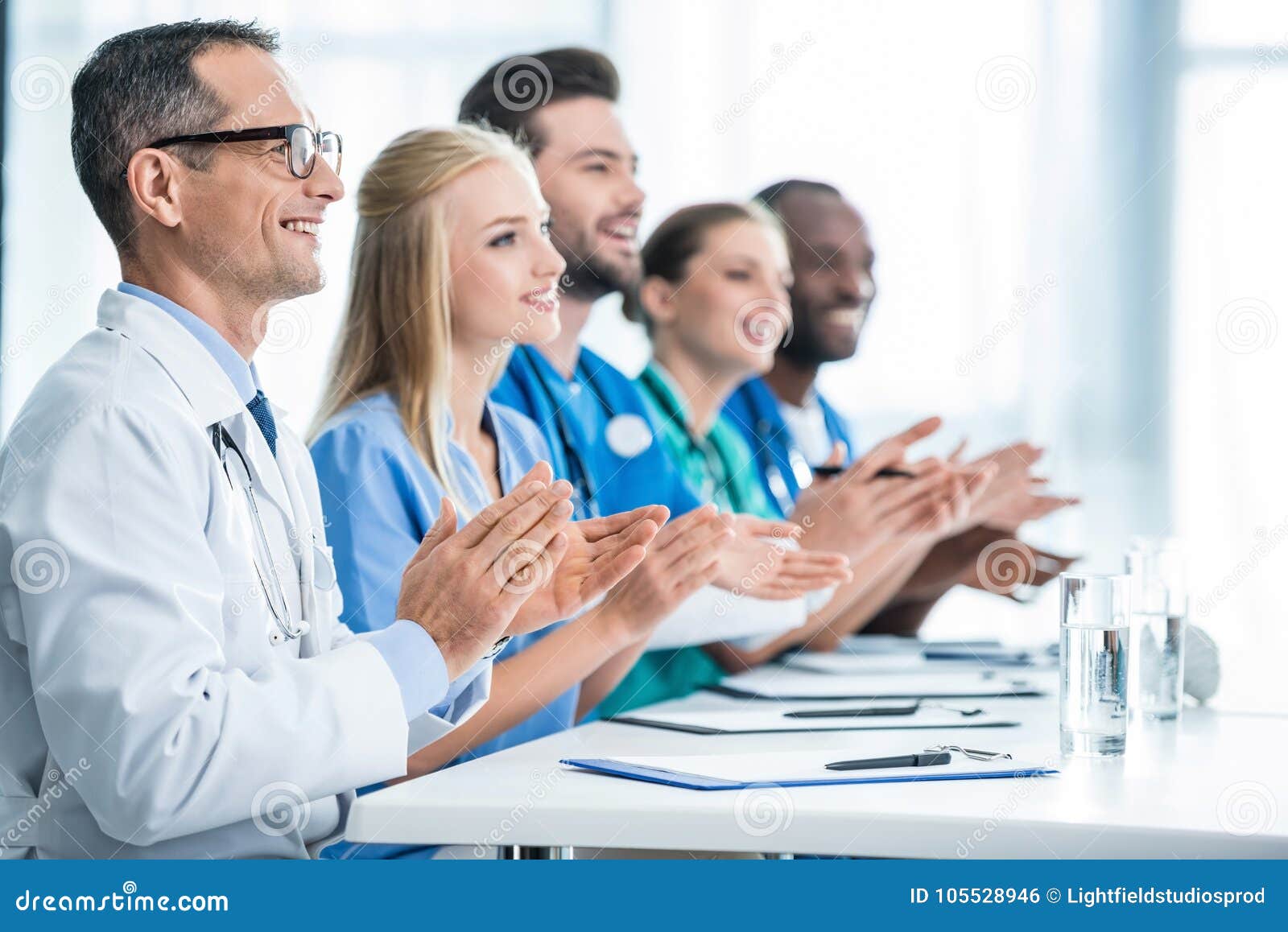 Doctors Sitting at Table and Clapping Stock Photo - Image of folders ...
