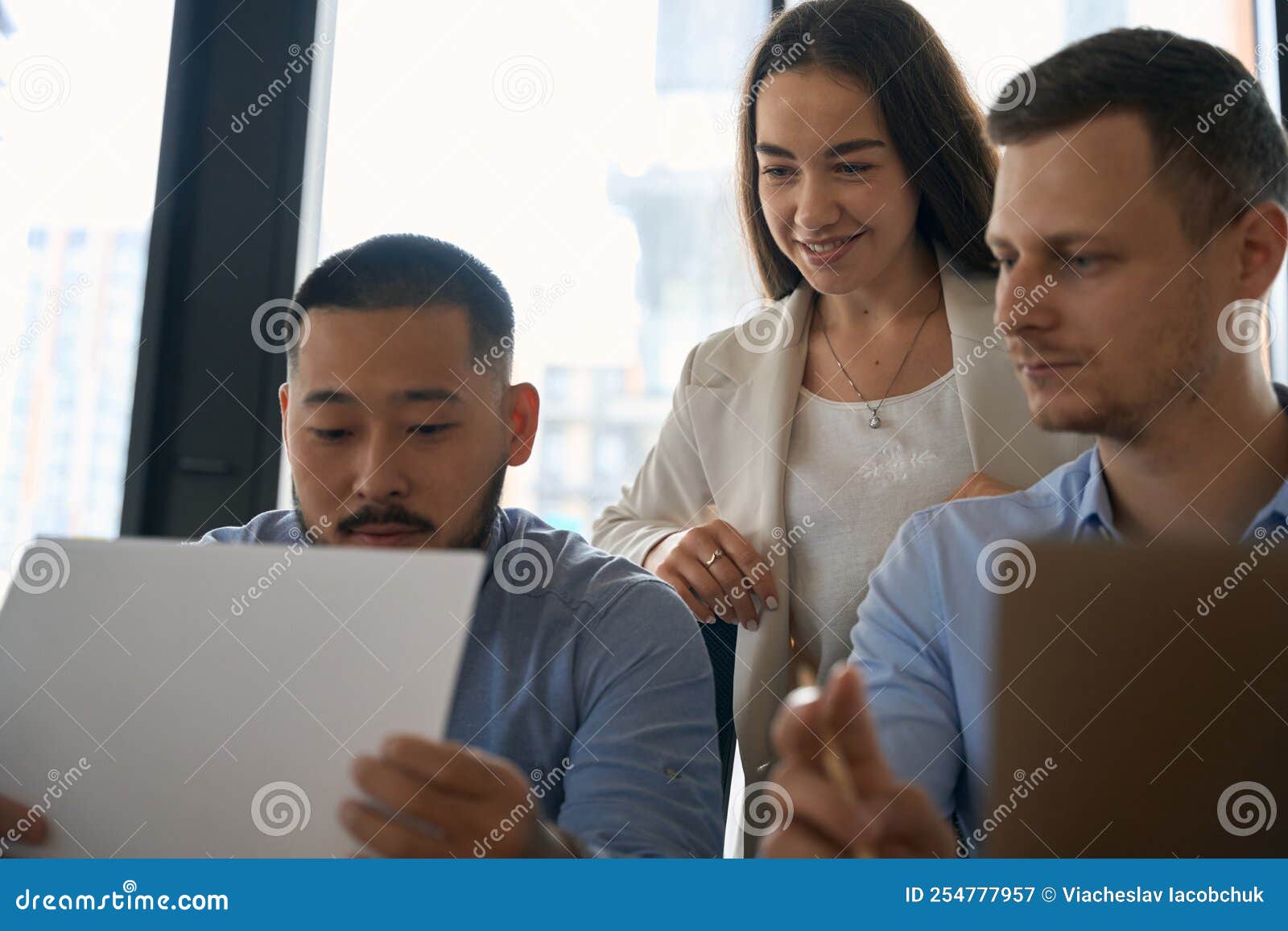 Team of Employees Discussing while Looking at Document in Office Stock ...
