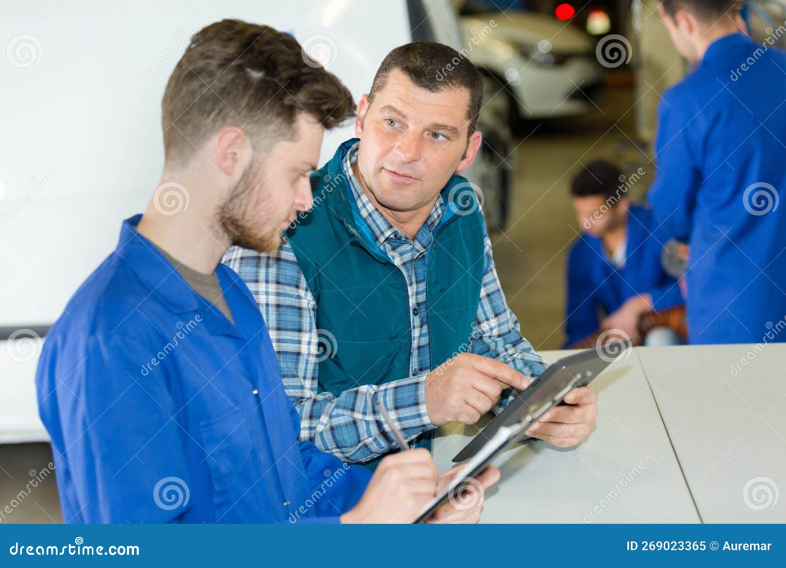 Team Mechanics Using Digital Tablet while Diagnosing Car Engine Stock ...