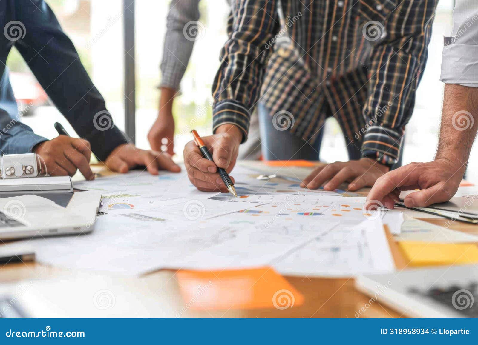 Team of Professionals Analyzing Project Plans on a Desk Filled with ...