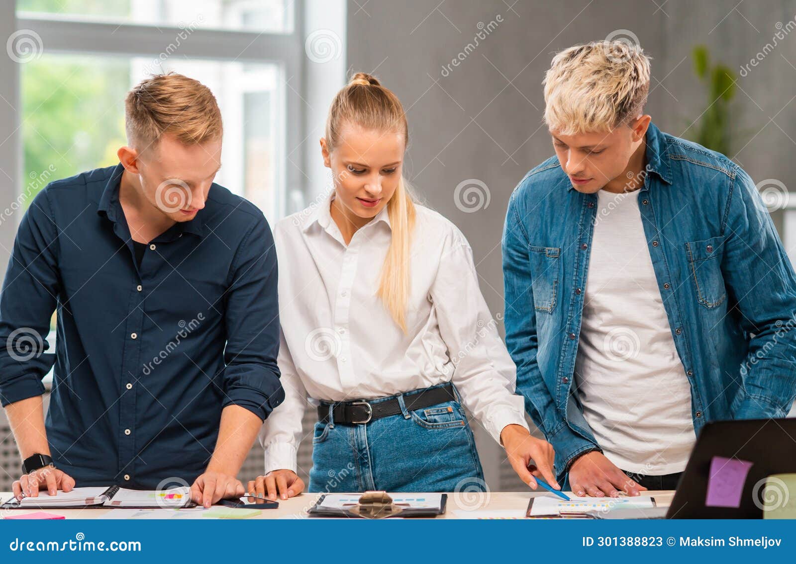 Team of Young and Confident Startupers is Working at the Table in the Office, Discussing the ...