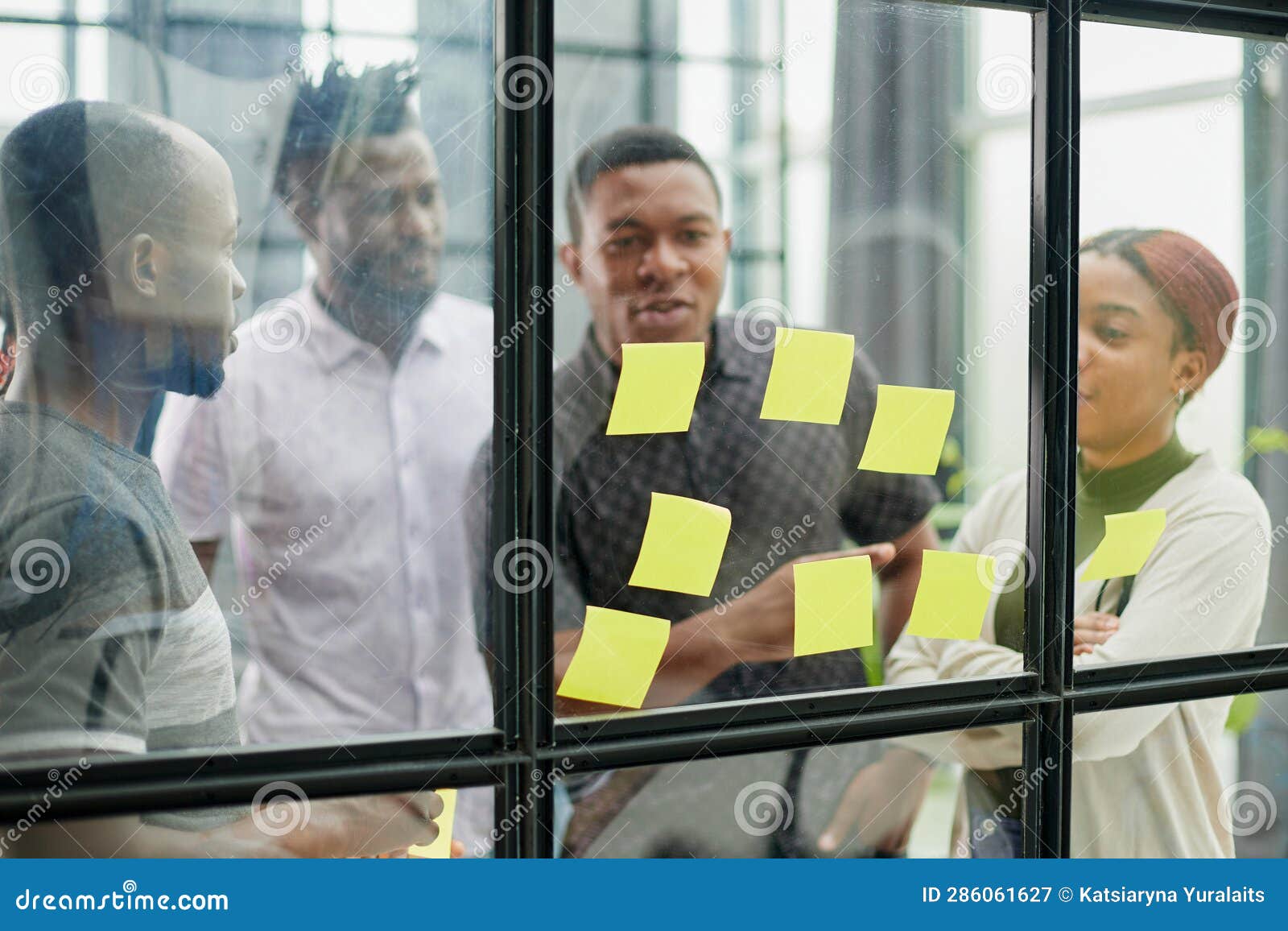 A Team of Young Designers Sticking Notes on Glass in a Modern Office ...