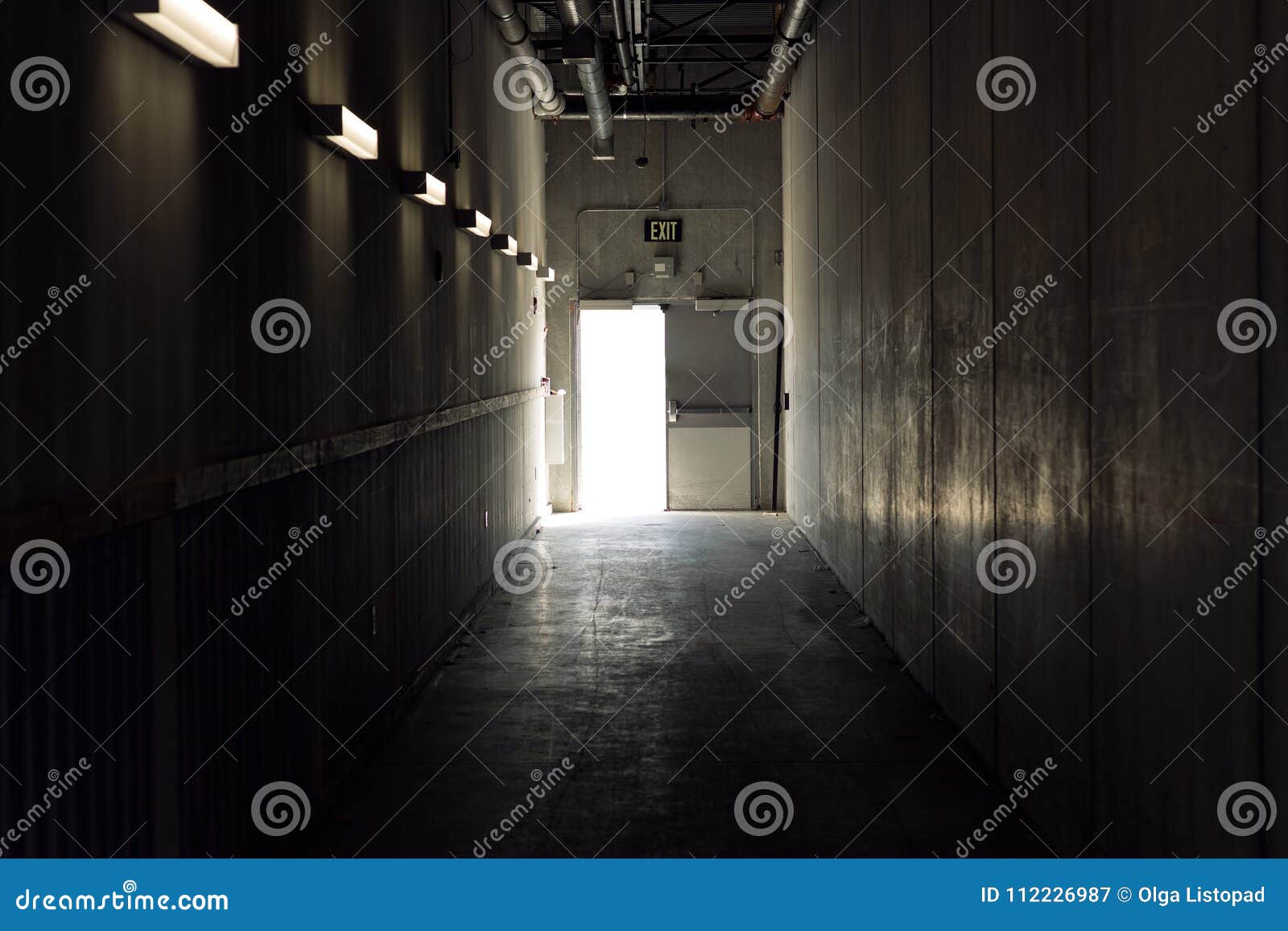 Technical Corridor with Light at the End. Exit Sign Above the Door ...