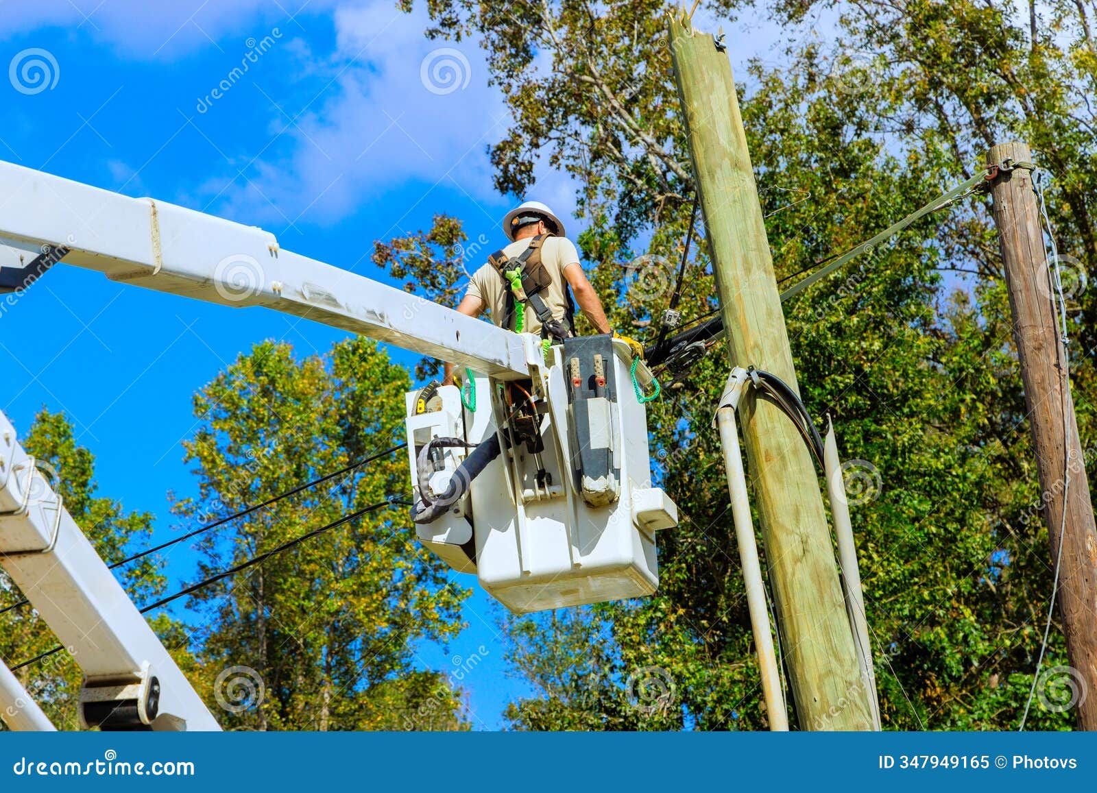 Technician Handles Wiring on Power Pole Using a Lift, Set Against Home ...
