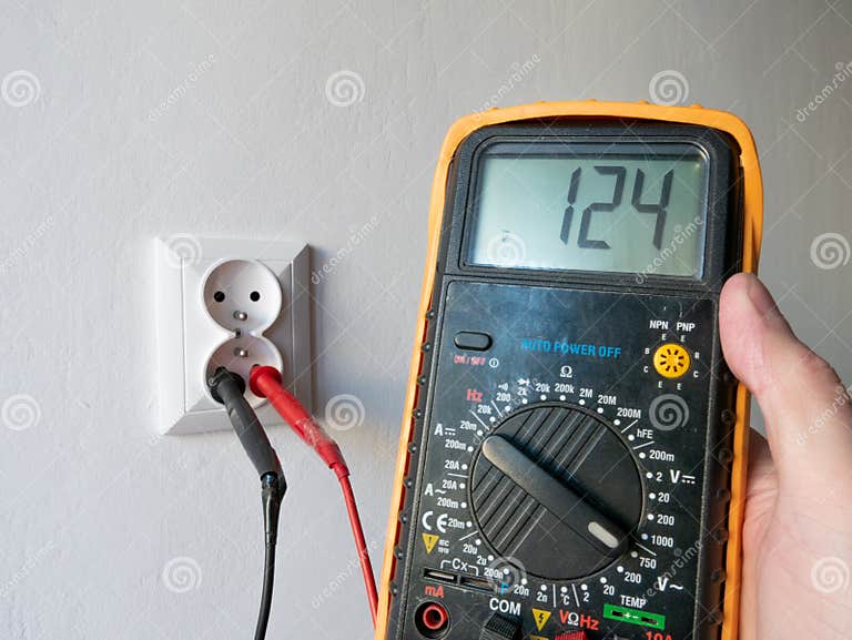 Hand Holding an Electric Multimeter in Front of the Electric Socket ...