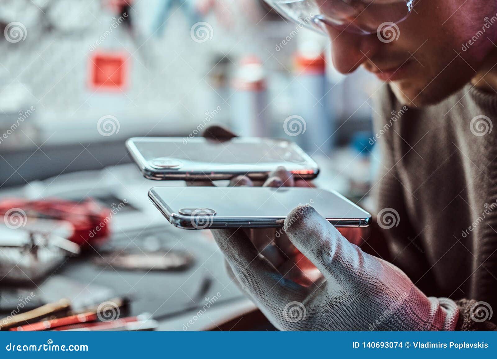 Technician Holds Two Identical Smartphones for Comparison, in One Hand ...