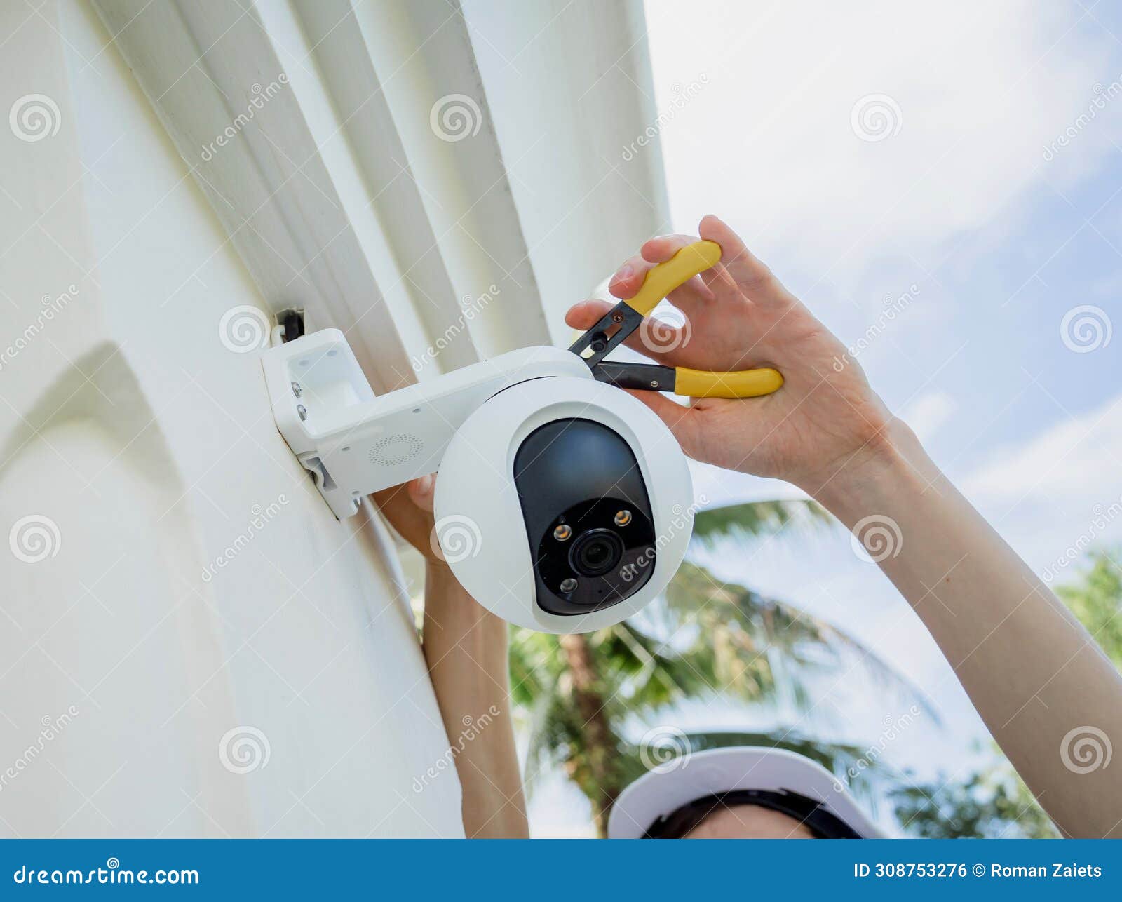 A Technician Installs a CCTV Camera on the Facade of a Residential ...