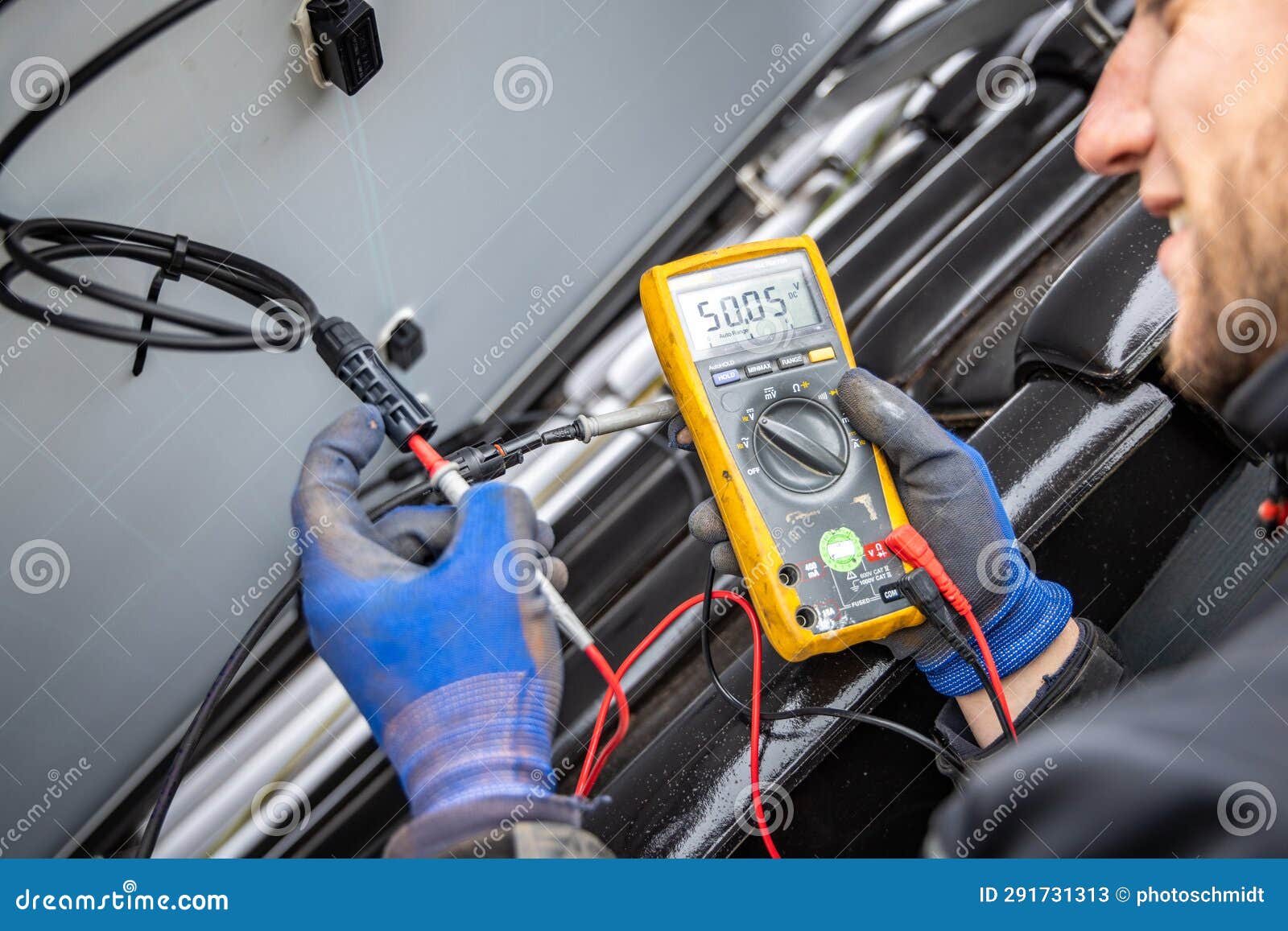 Technician with a Multimeter Testing a Solar Panel on a Roof for Its ...
