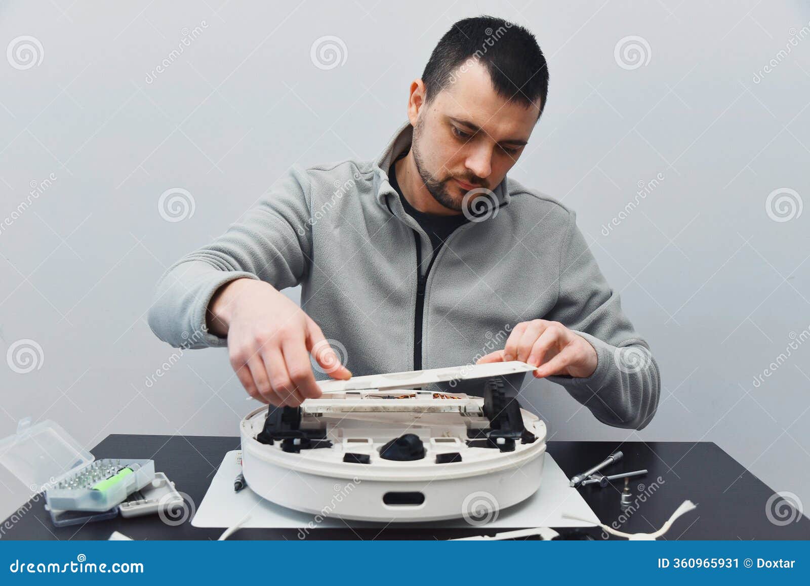 Technician Performs Maintenance on a Robotic Vacuum Cleaner, Adjusting ...