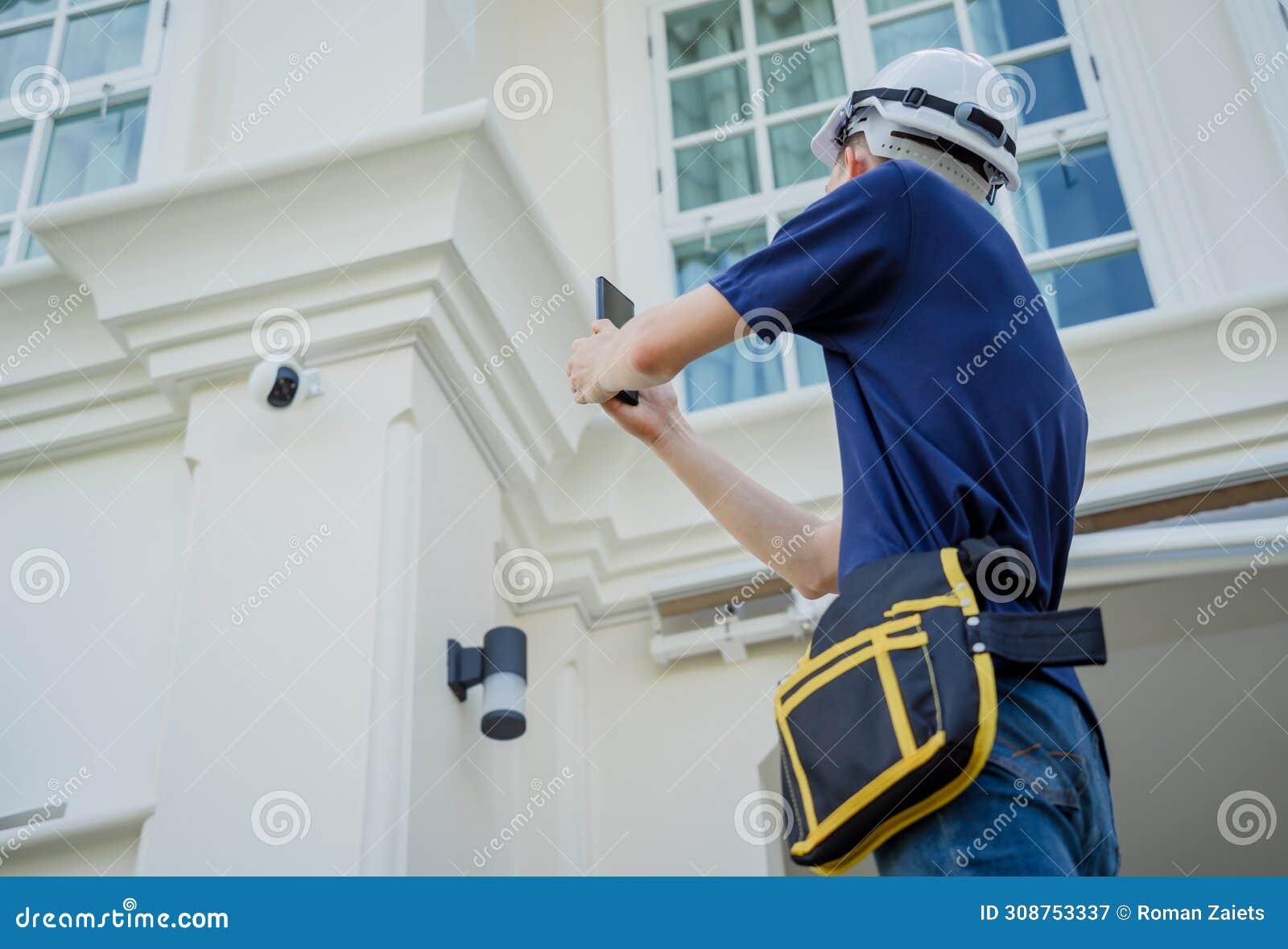 A Technician Sets Up a CCTV Camera on the Facade of a Residential ...