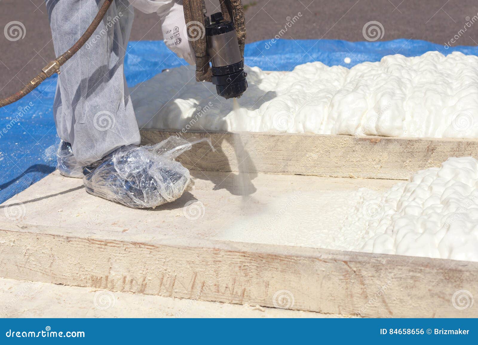 Technician Spraying Blown Fiberglass Insulation Between Attic Trusses ...