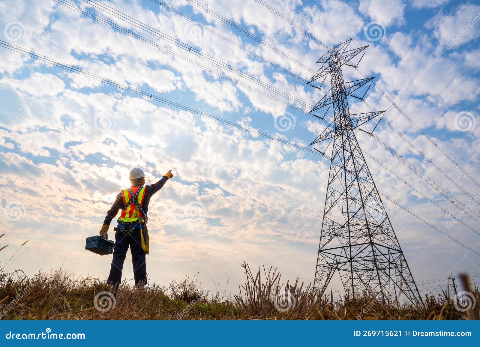 A Technician Stands Holding a Toolbox while Pointing at a High-voltage ...