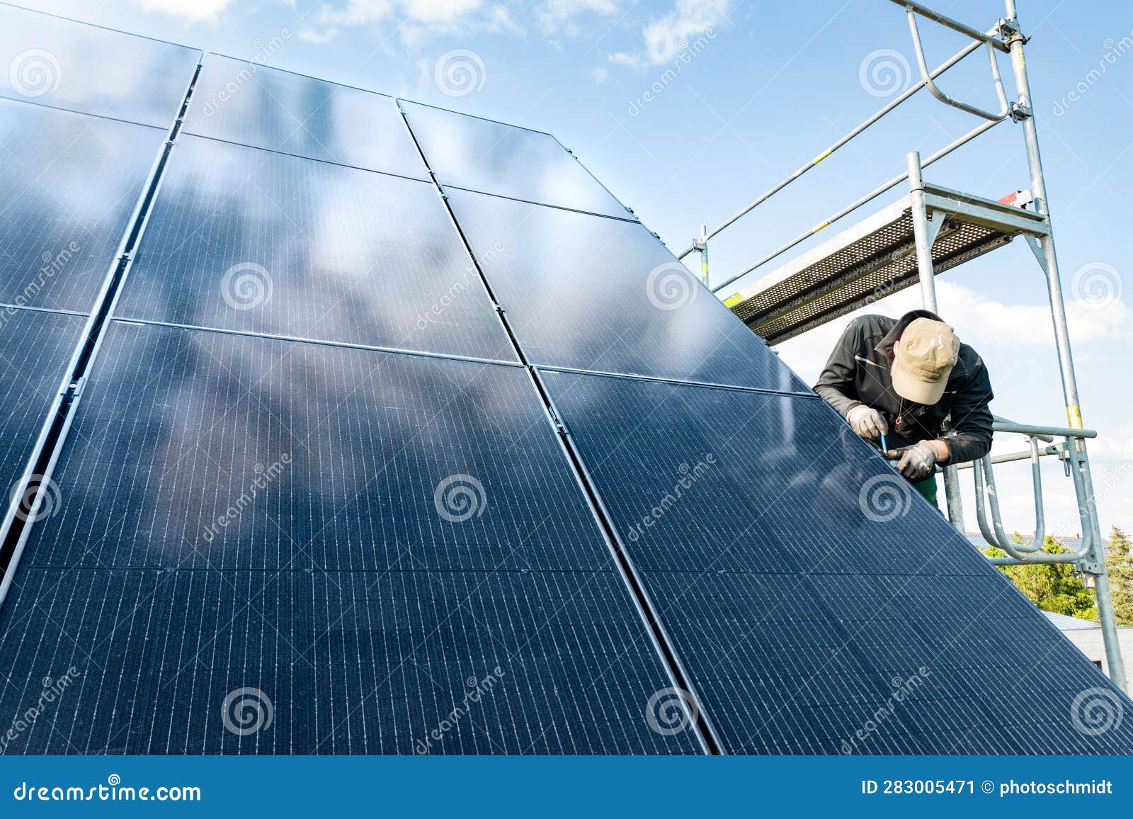 Technician Working on a Solar Panel Array on Top of the Roof of a House ...