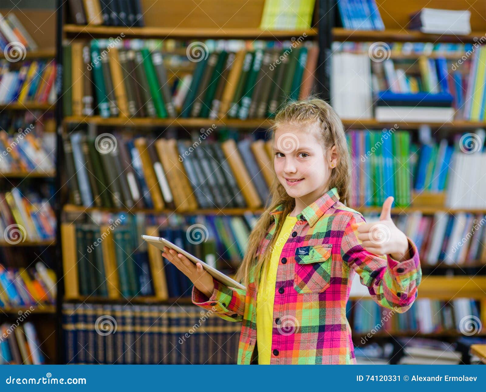 Teen Girl Using a Tablet Computer in a Library and Showing Thumb Stock ...