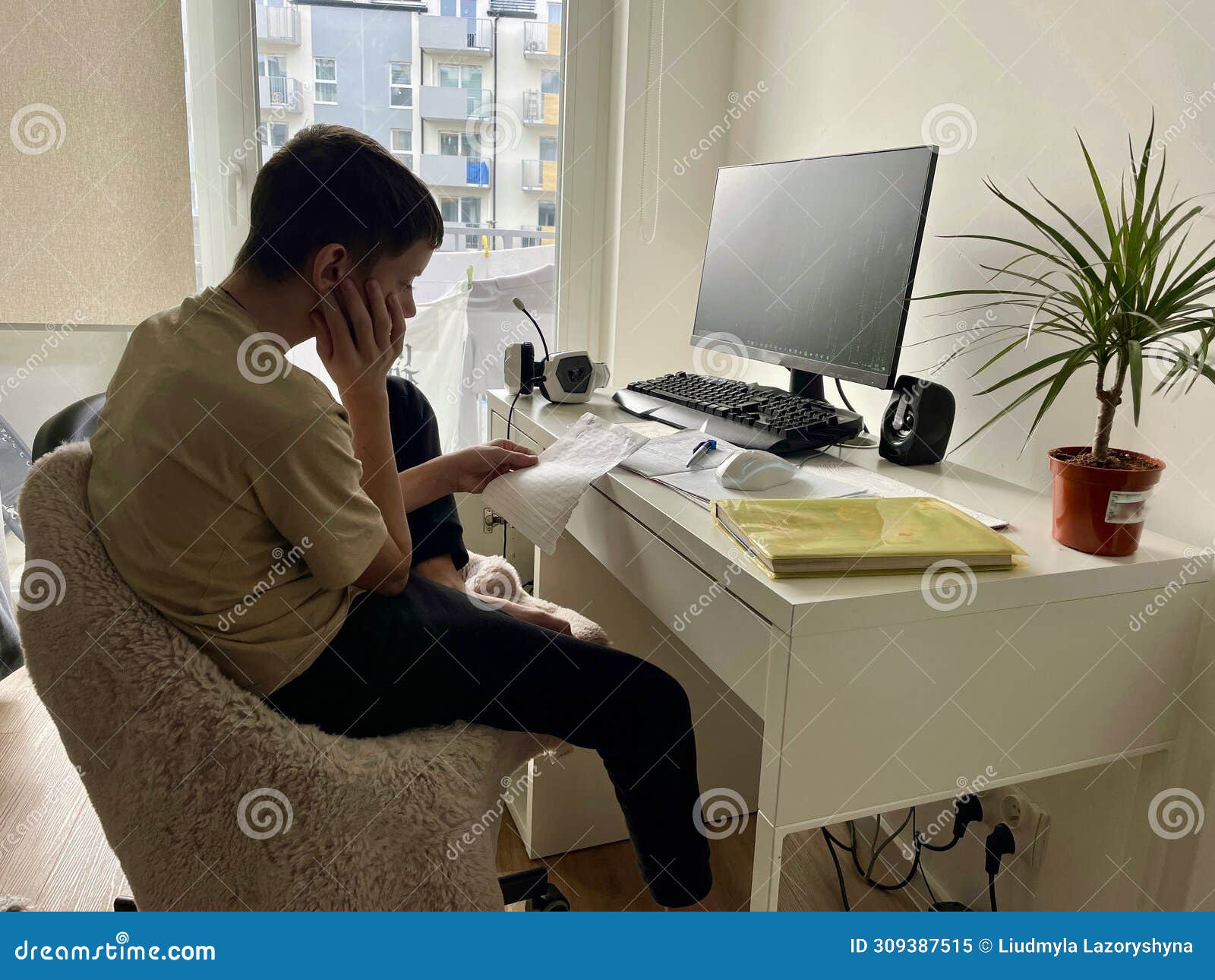 A Teenage Boy Does Homework in Front of a Computer Monitor. Stock Image ...
