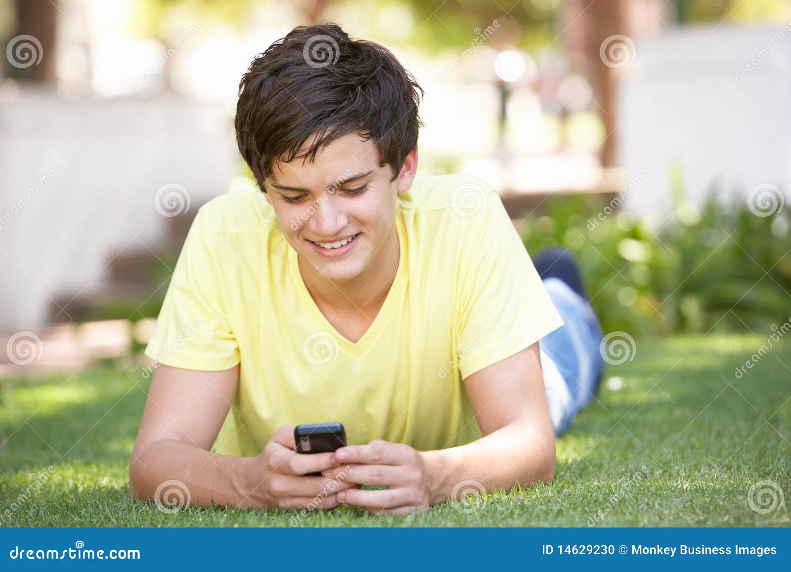 Teenage Boy Laying In Park Using Mobile Phone Stock Photography ...
