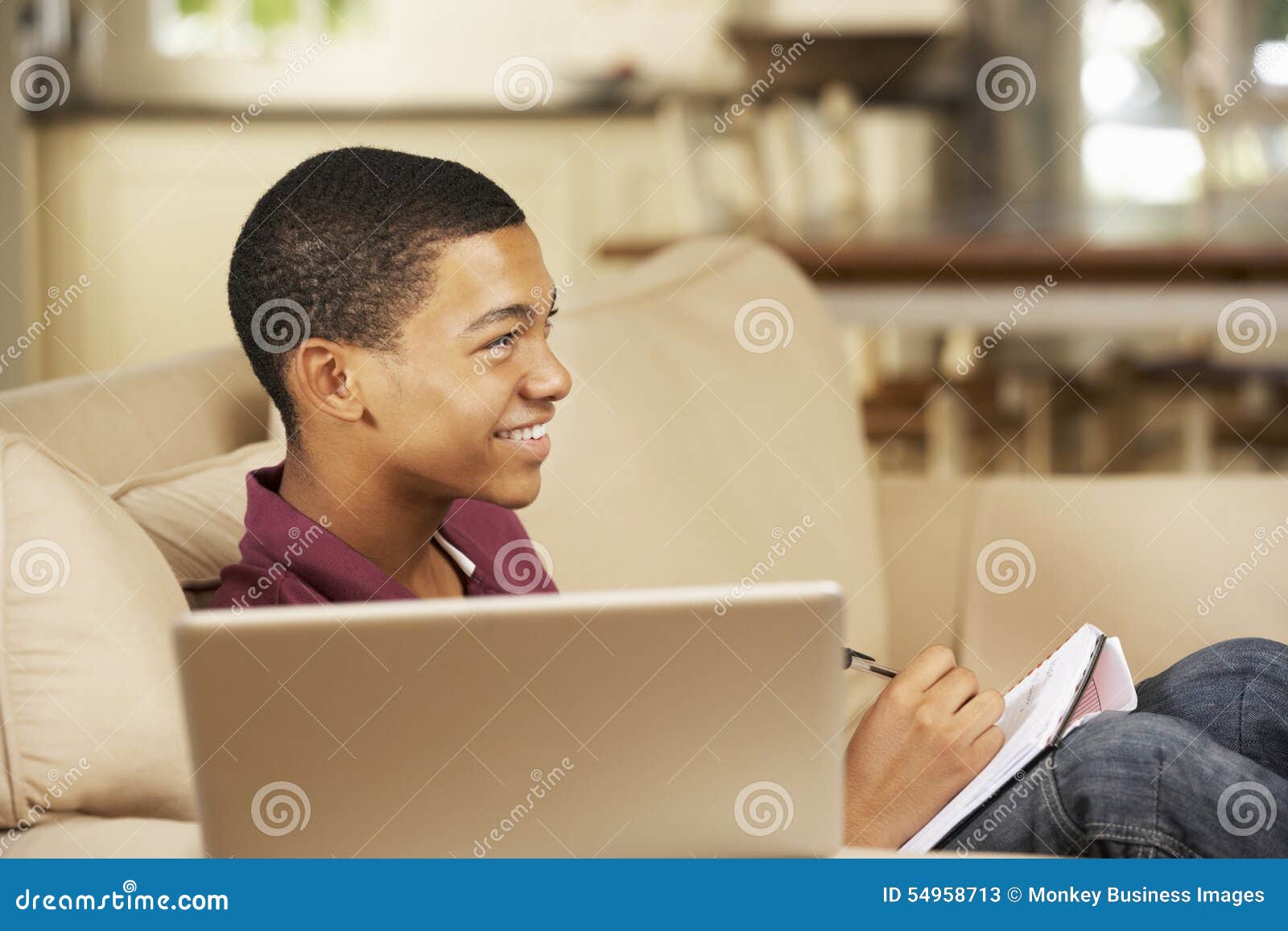 Teenage Boy Sitting on Sofa at Home Doing Homework Using Laptop ...