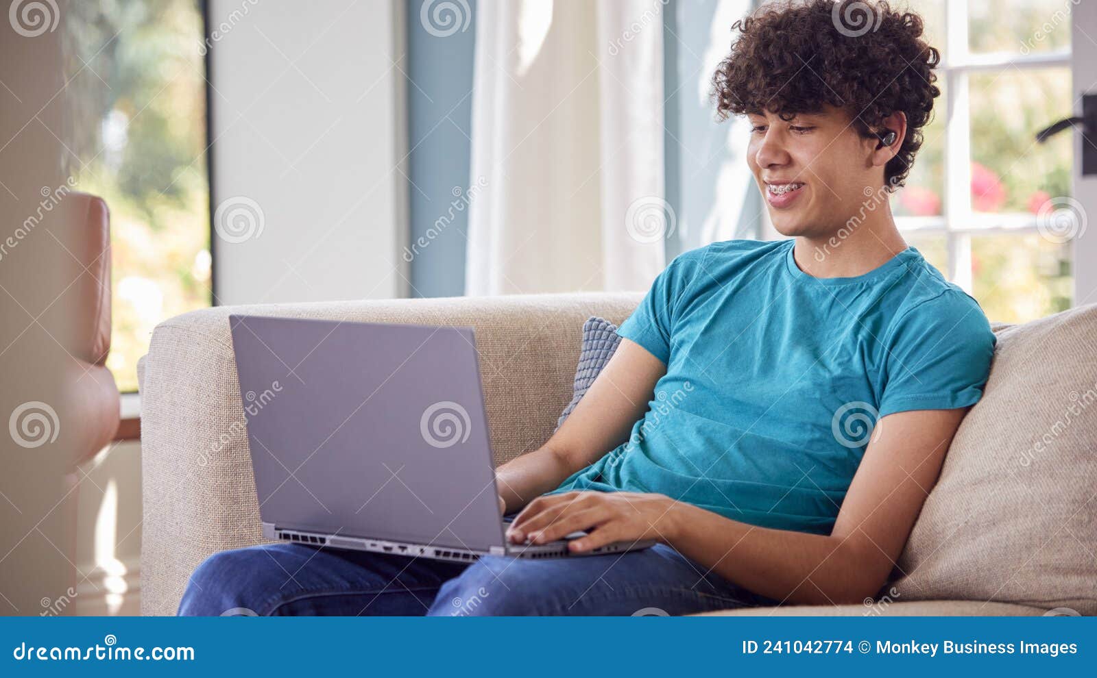 Teenage Boy Sitting on Sofa at Home Using Laptop Computer Stock Photo ...