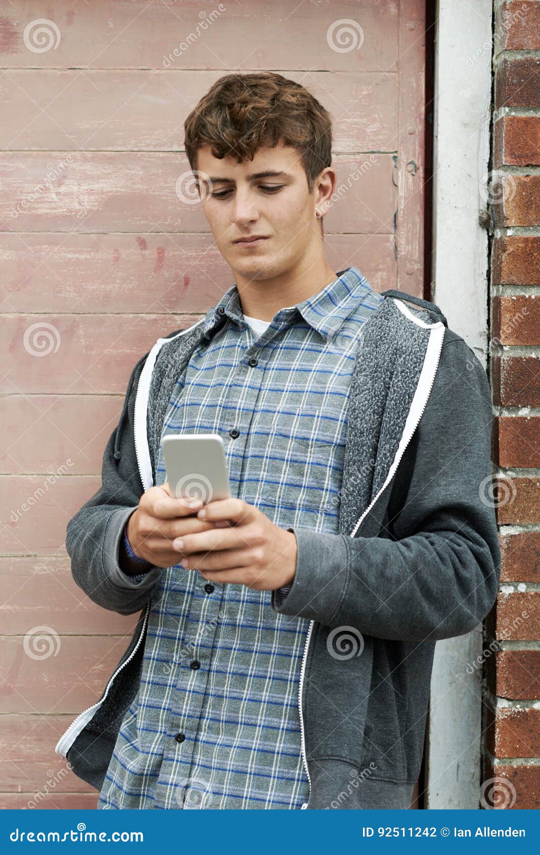 Teenage Boy Texting on Mobile Phone in Urban Setting Stock Photo ...