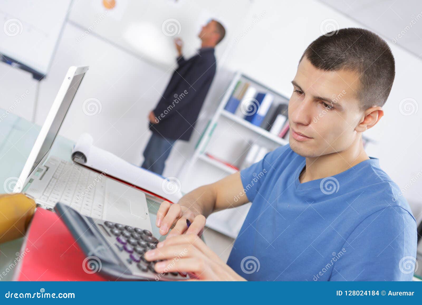 Teenage Boy Using Calculator while Studying at Desk in Classroom Stock ...