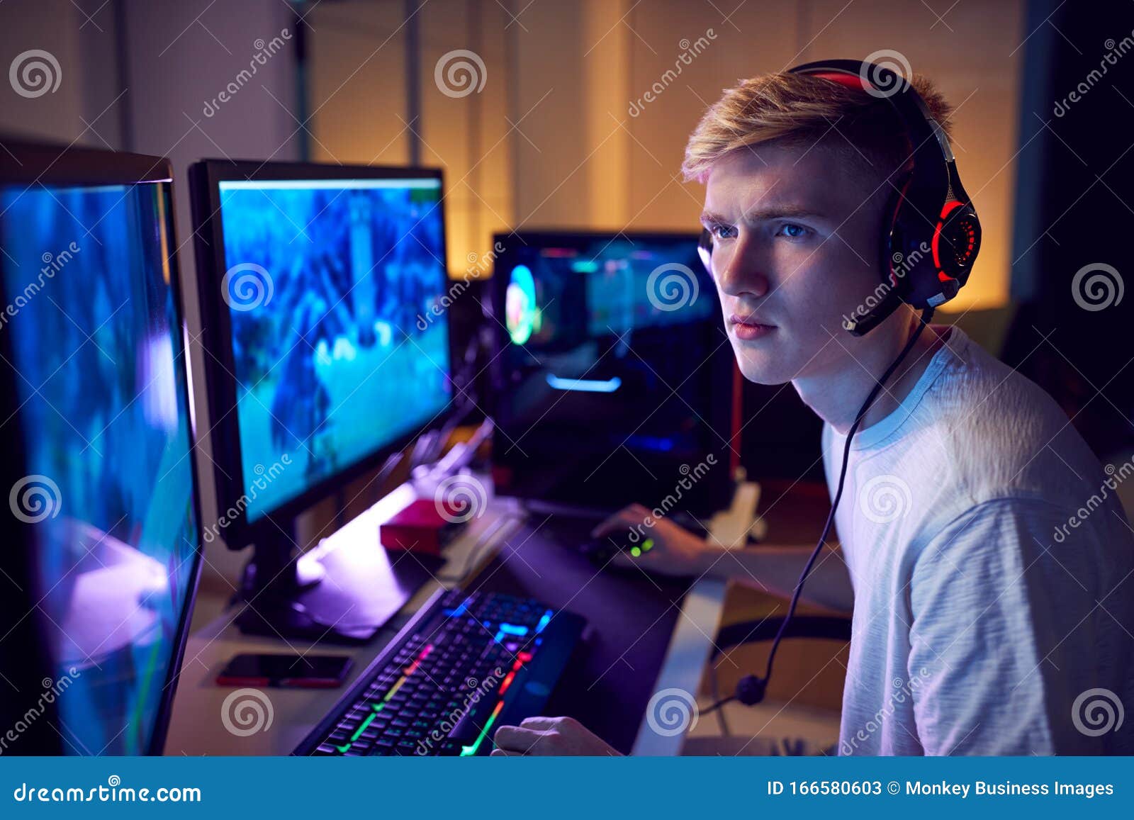 Teenage Boy Wearing Headset Gaming at Home Using Dual Computer Screens ...