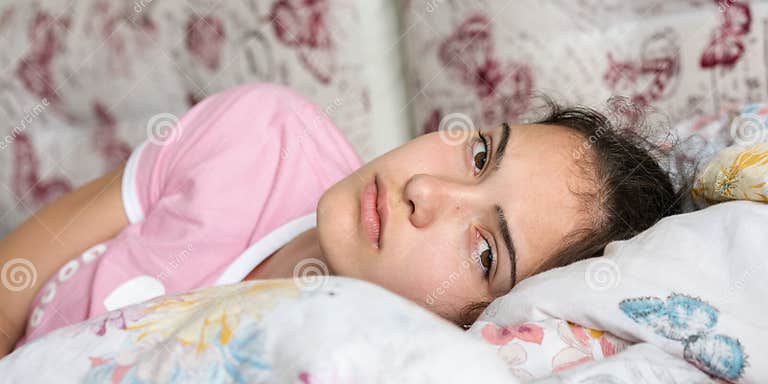 Teenage Brunette Wakes Up Looking Straight And Lying In Bed Stock Image